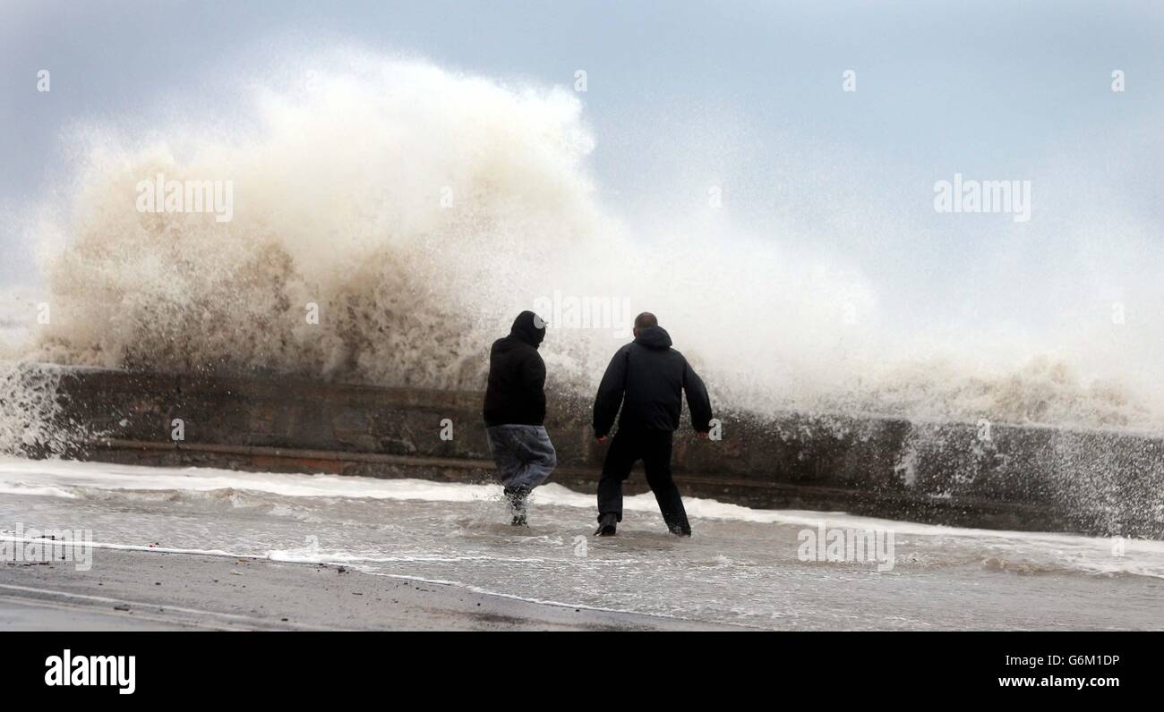 People look at the huge waves as they walk along the seafront in Rhyl ...