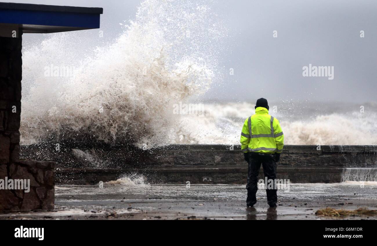 A man stands in front of a huge wave on the seafront in Rhyl as heavy ...