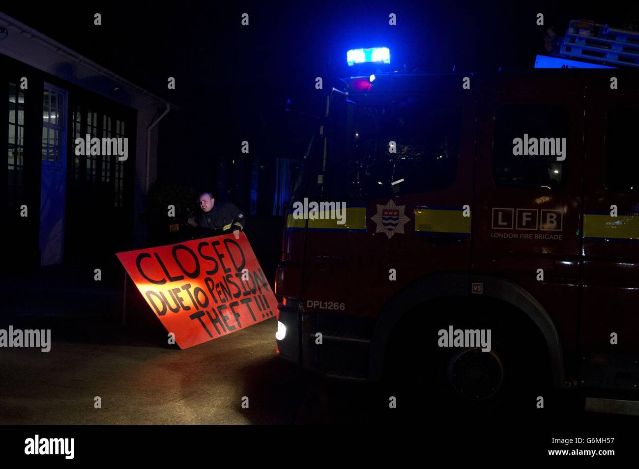 A firefighter moves a poster as a fire engine returns to Euston Fire ...