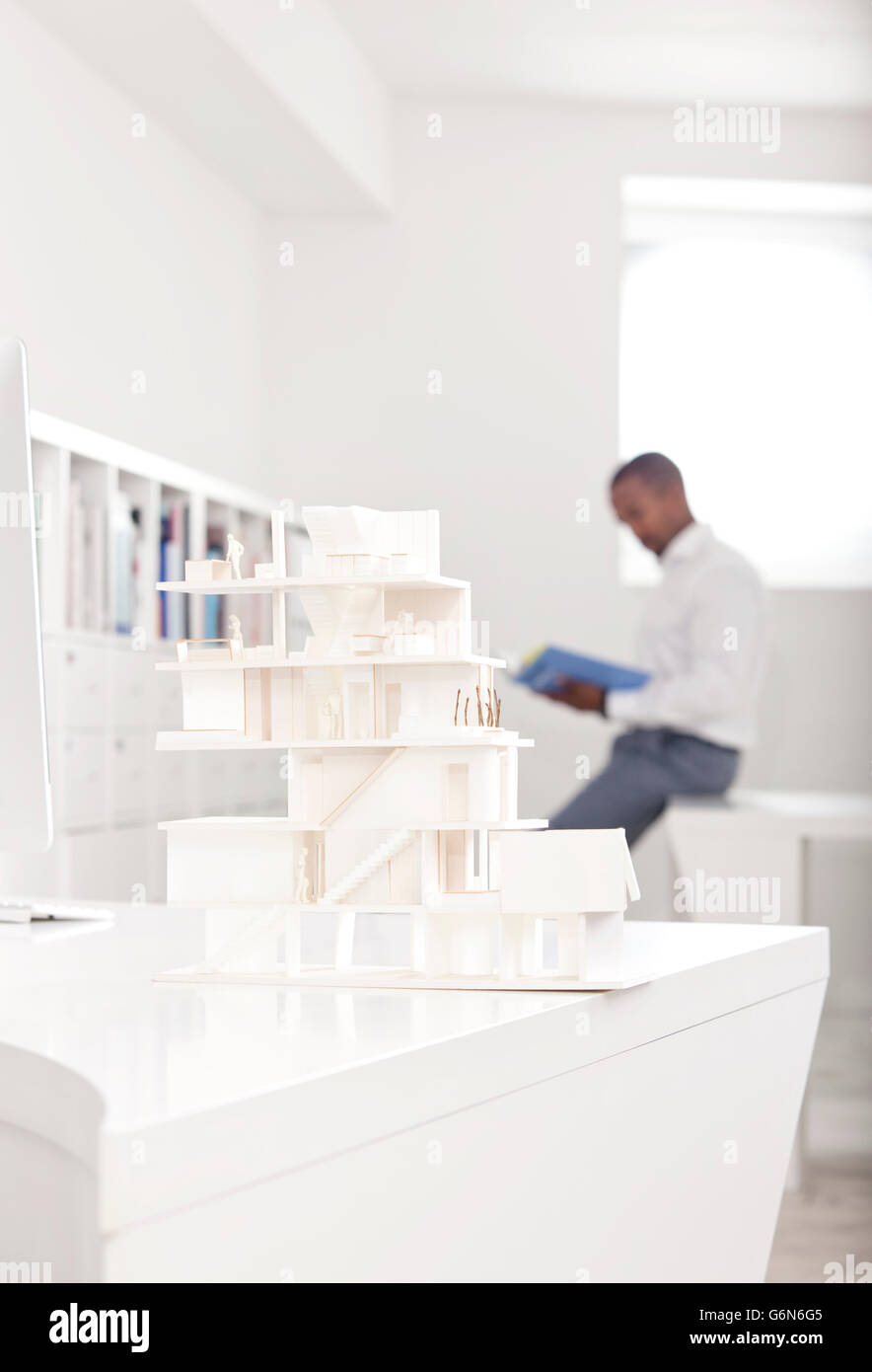 Architectural model on desk in an office with reading man in the ...