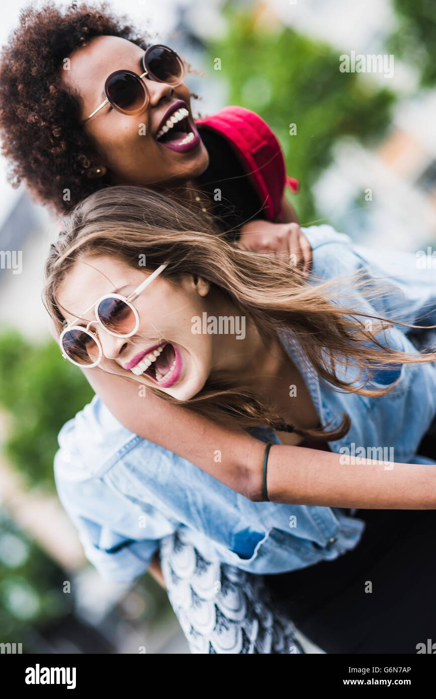 Laughing woman giving her friend a piggyback ride Stock Photo - Alamy