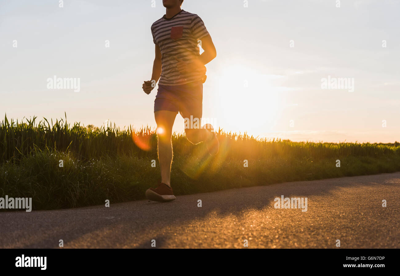 Germany, young man jogging, against the sun Stock Photo - Alamy