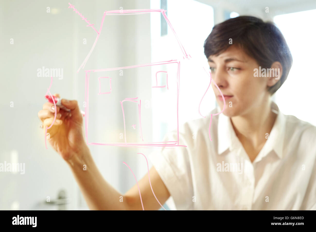 Woman drawing a house on glass pane in an office Stock Photo - Alamy