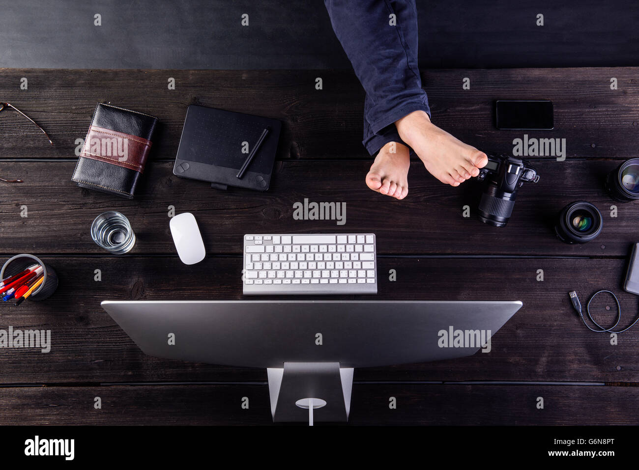 Man sitting at desk with computer and camera having his feet up Stock ...