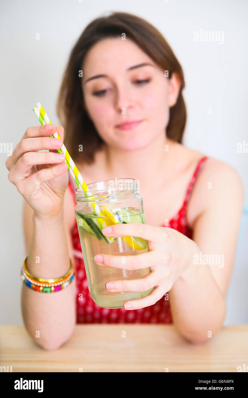 Woman holding glass of detox water infused with lemon and cucumber ...