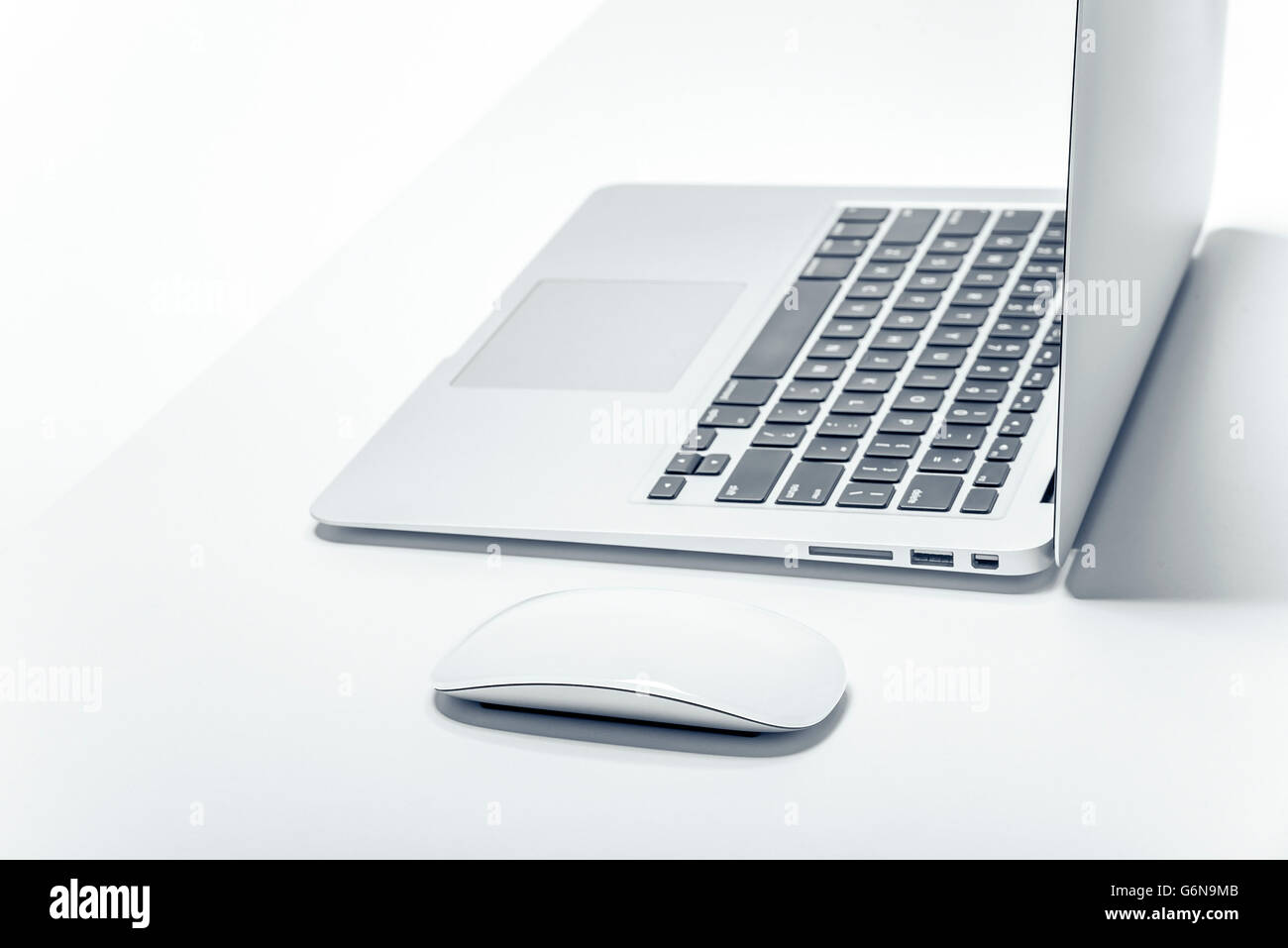 Laptop computer on white table with mouse. Filters added Stock Photo ...