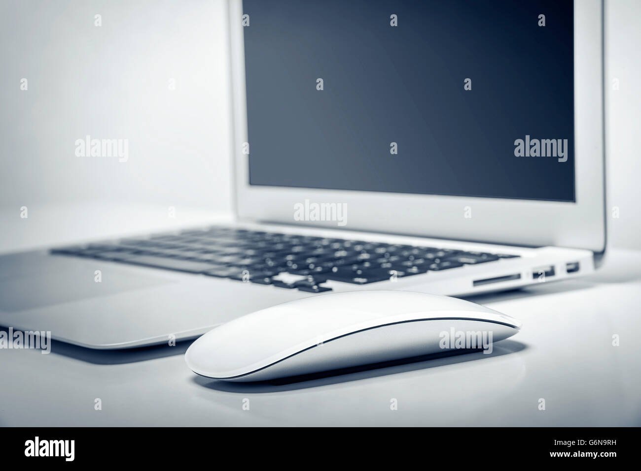 Laptop computer on white table with mouse. Filters added Stock Photo ...