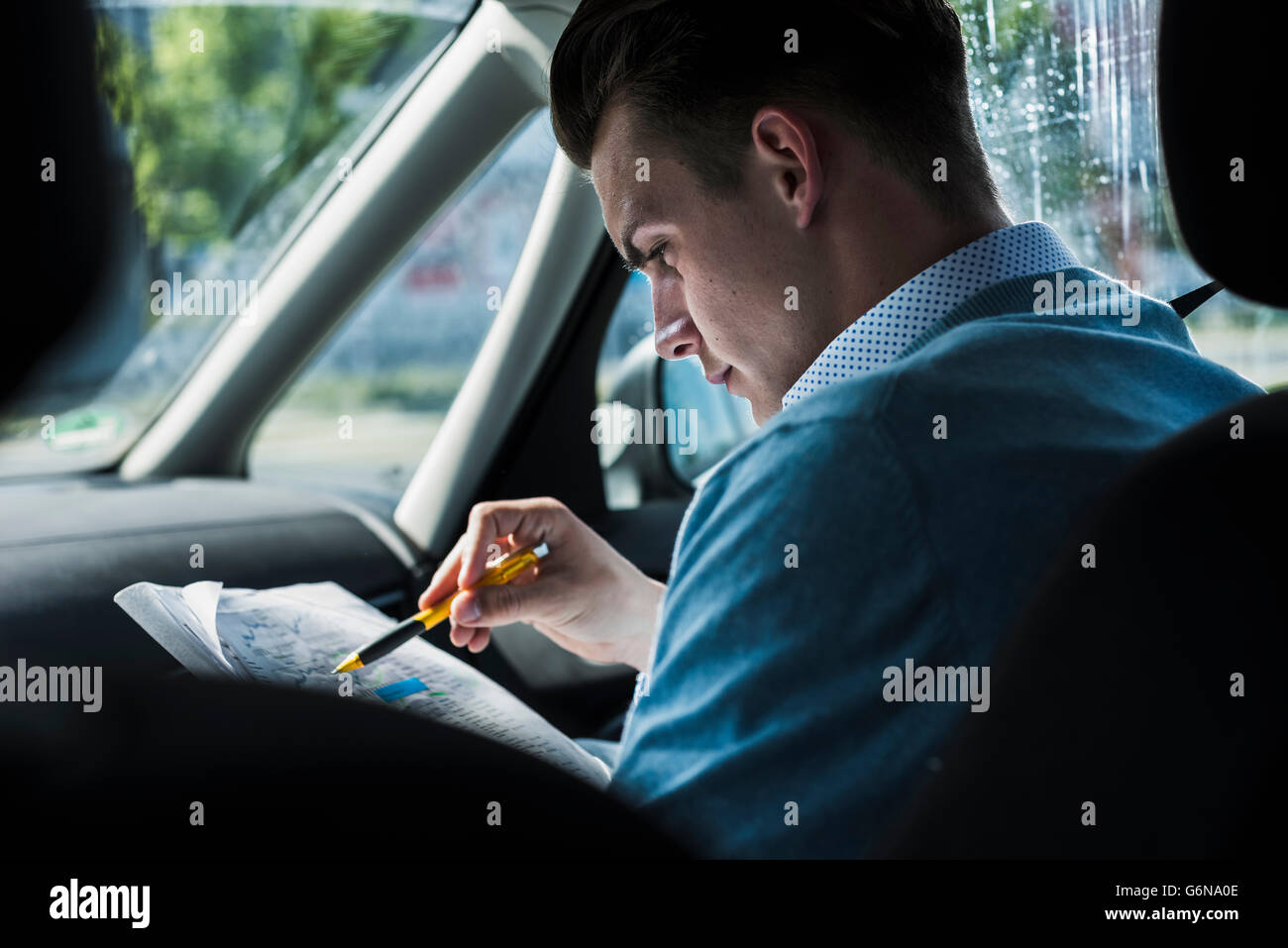 Young man reading document in car Stock Photo - Alamy