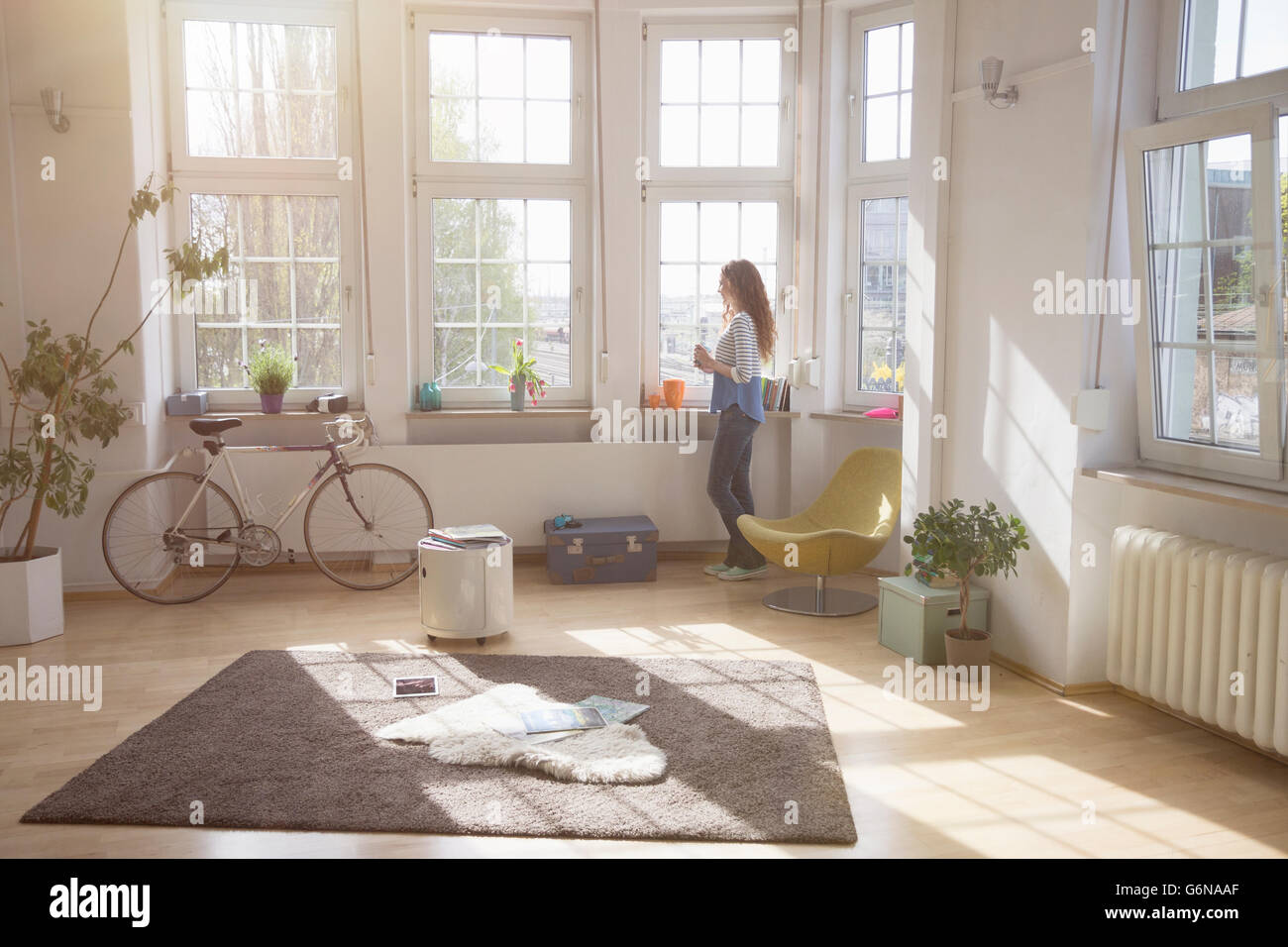 Woman at home looking out of window Stock Photo - Alamy