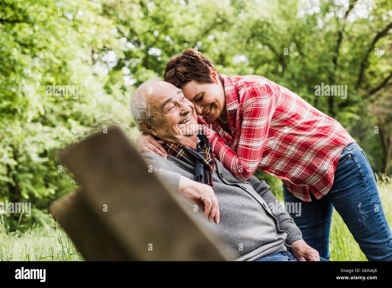 Happy woman hugging her old father sitting on a bench in nature Stock ...