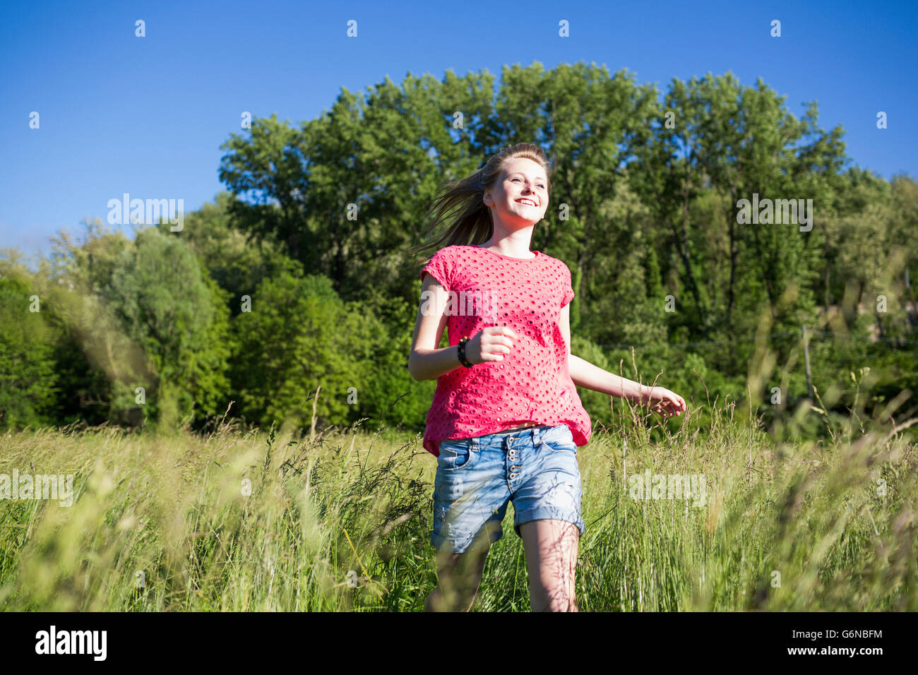 Happy teenage girl running on a meadow Stock Photo - Alamy