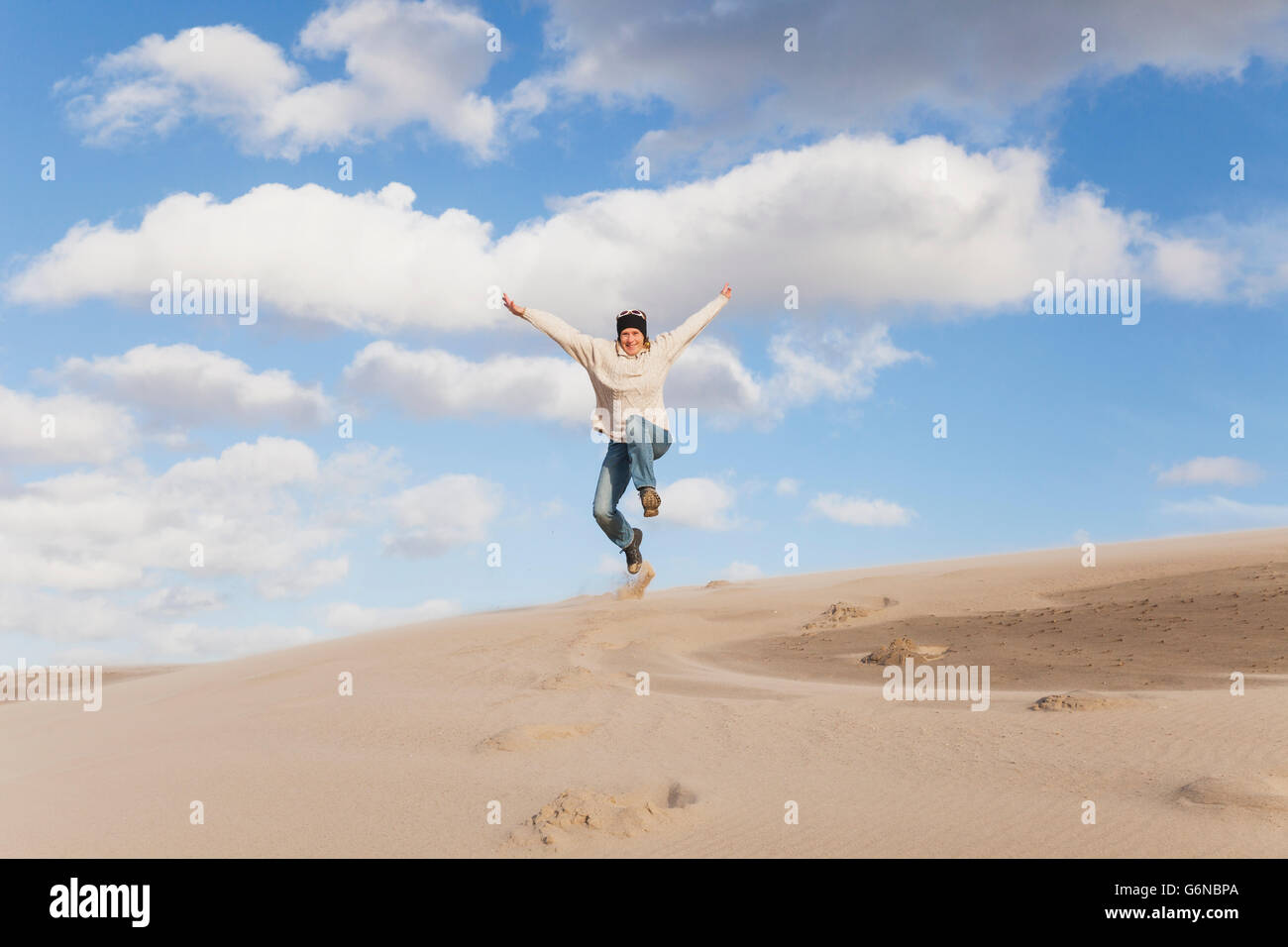 Enthusiastic mature woman jumping over sand dune Stock Photo - Alamy