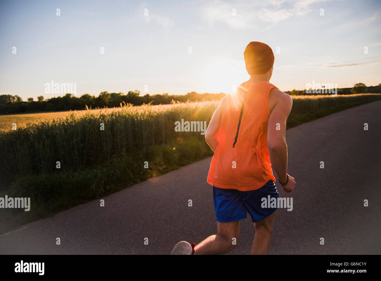 Germany, young man jogging, against the sun Stock Photo - Alamy