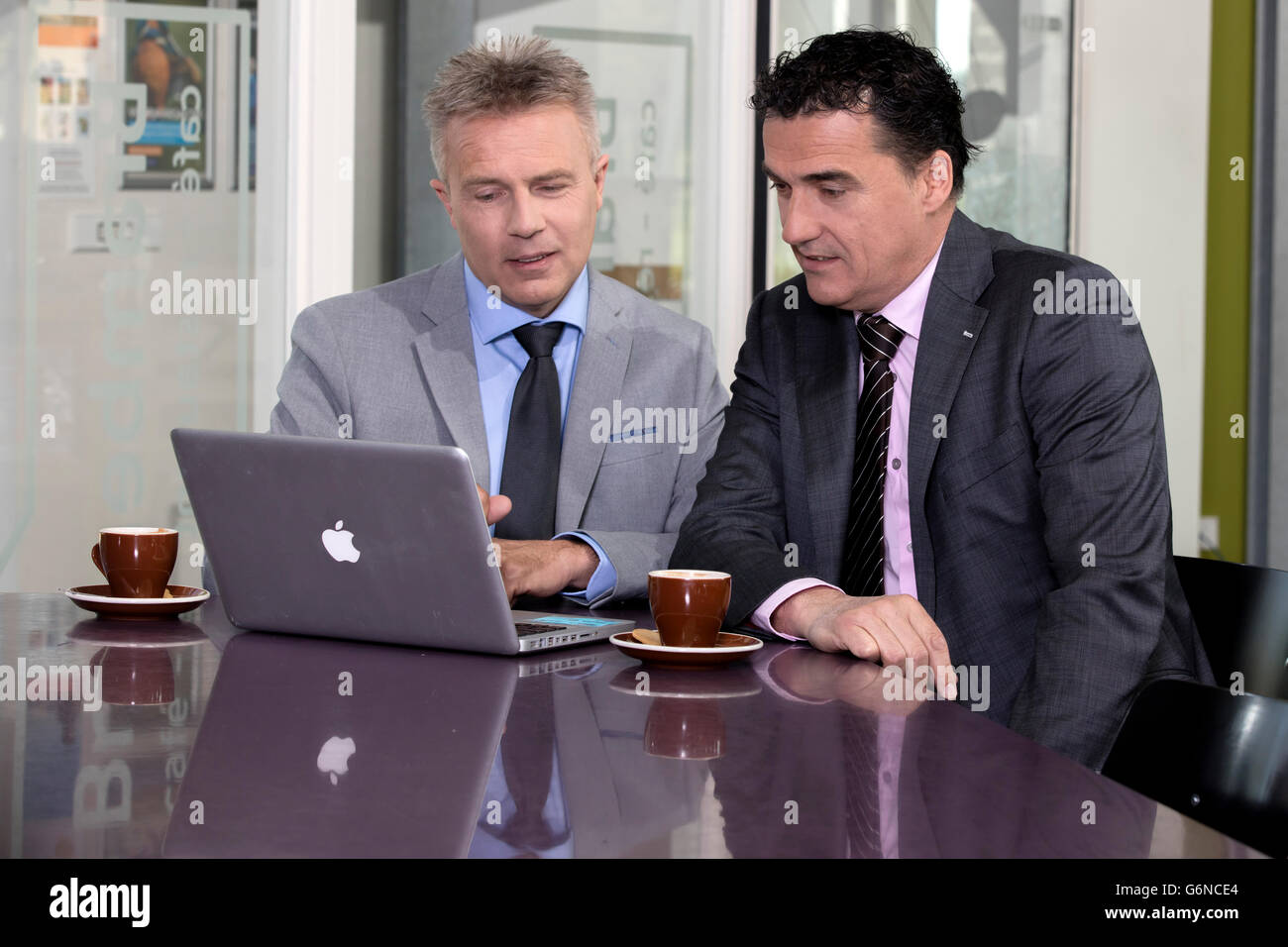 Two confident and successful businessmen at table brainstorming ideas ...