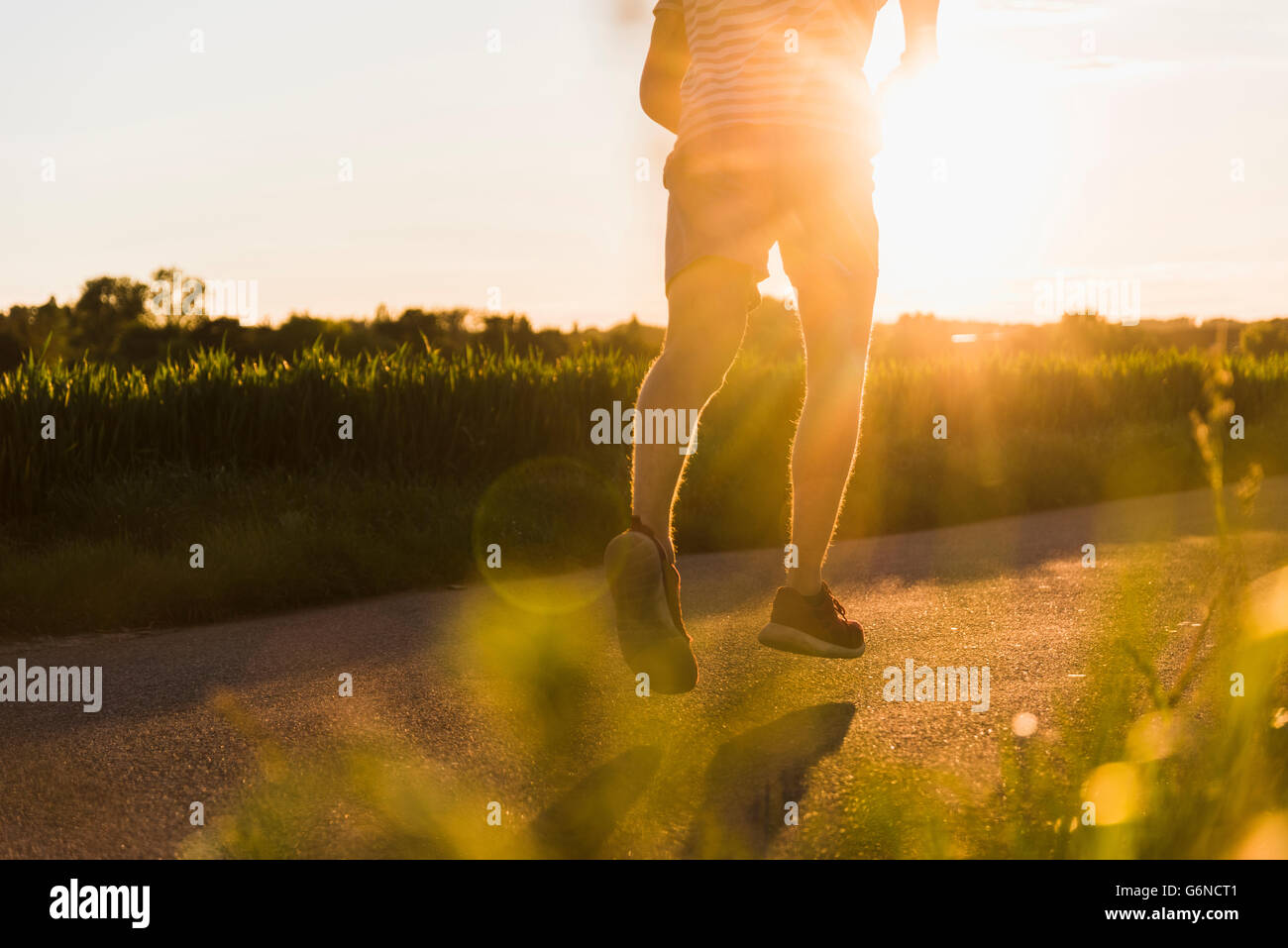 Germany, young man jogging, against the sun Stock Photo - Alamy