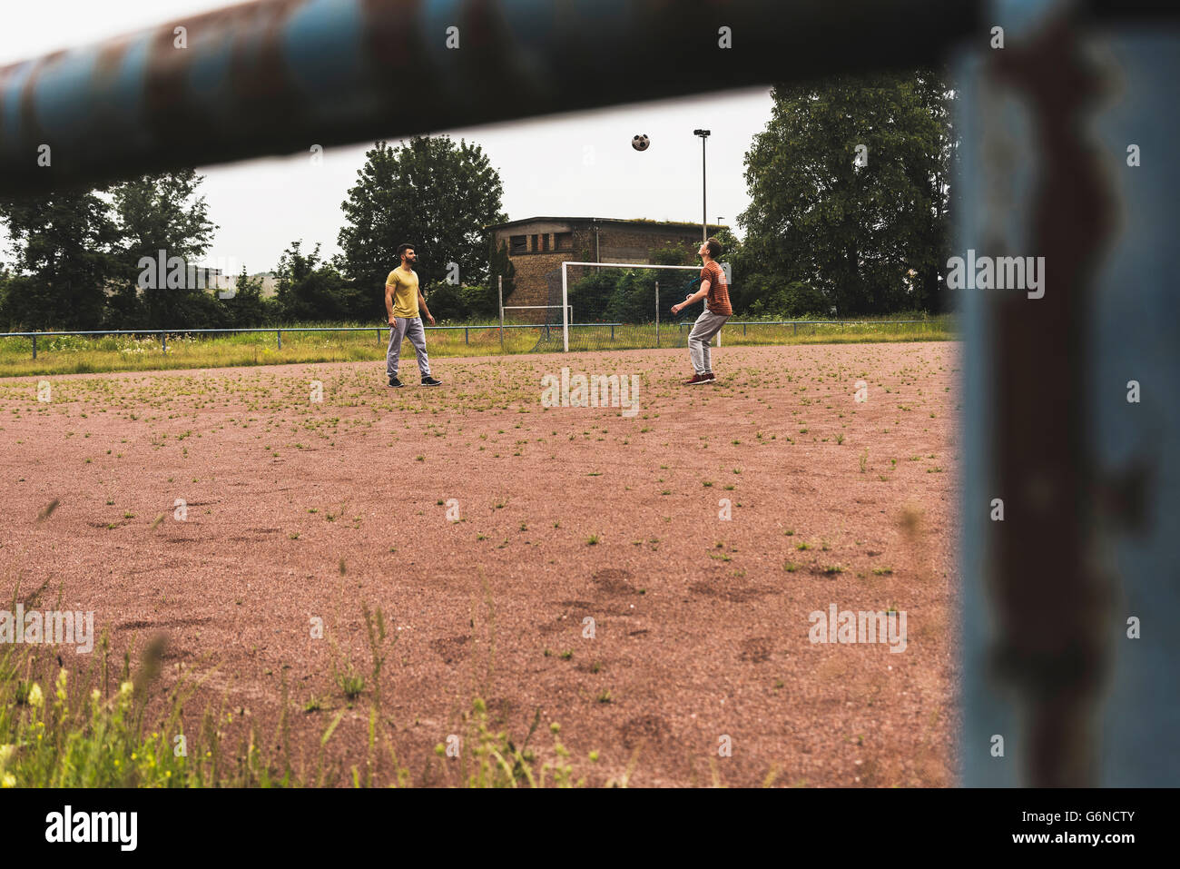 Two men playing football on cinder pitch Stock Photo - Alamy