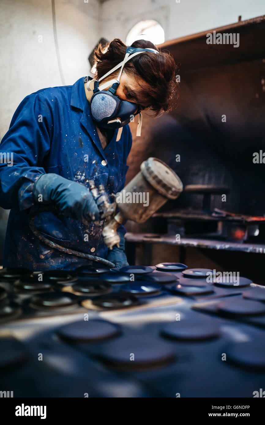 Female worker painting ceramics with spray gun Stock Photo - Alamy