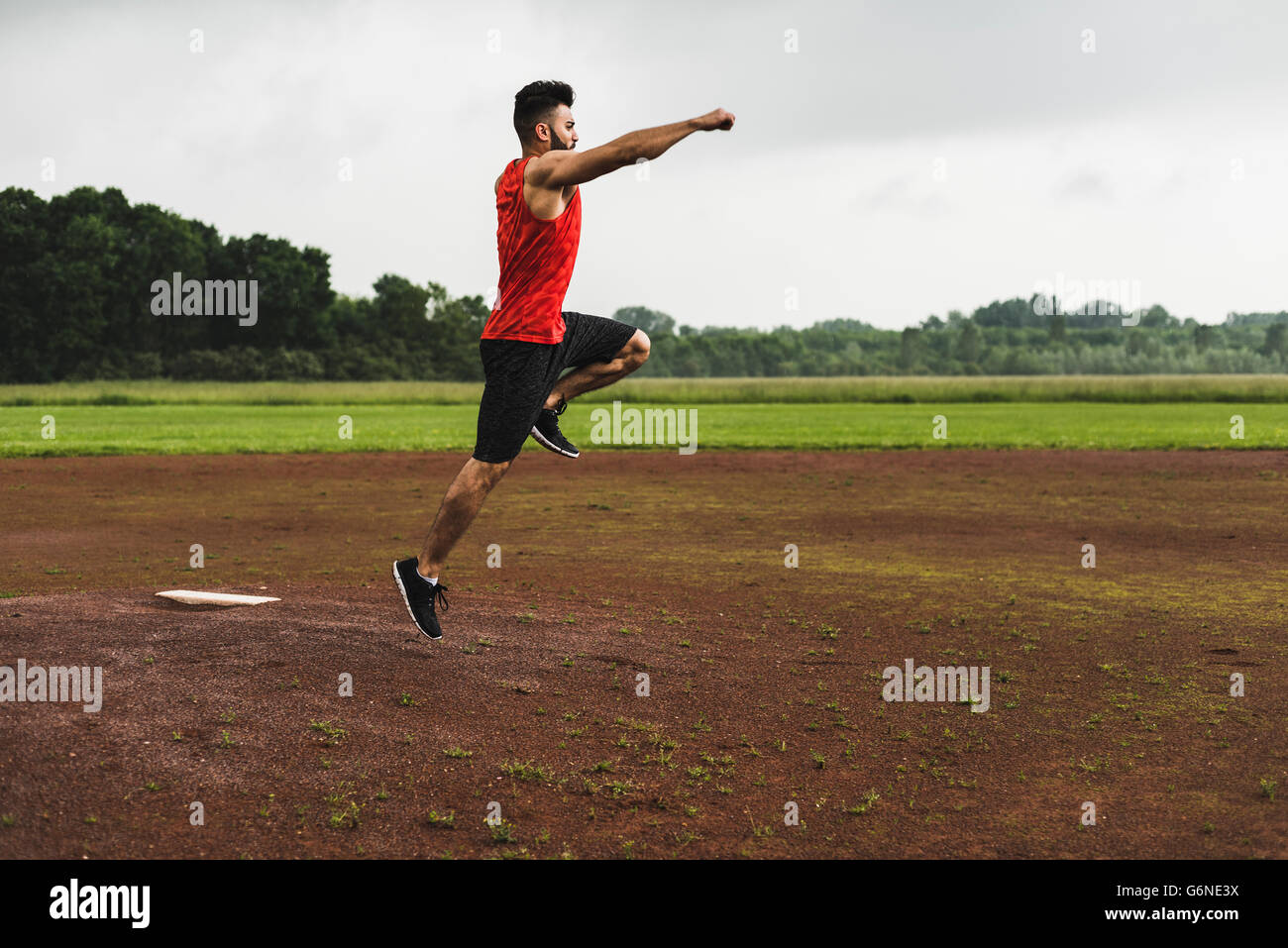 Athlete jumping on sports field Stock Photo - Alamy