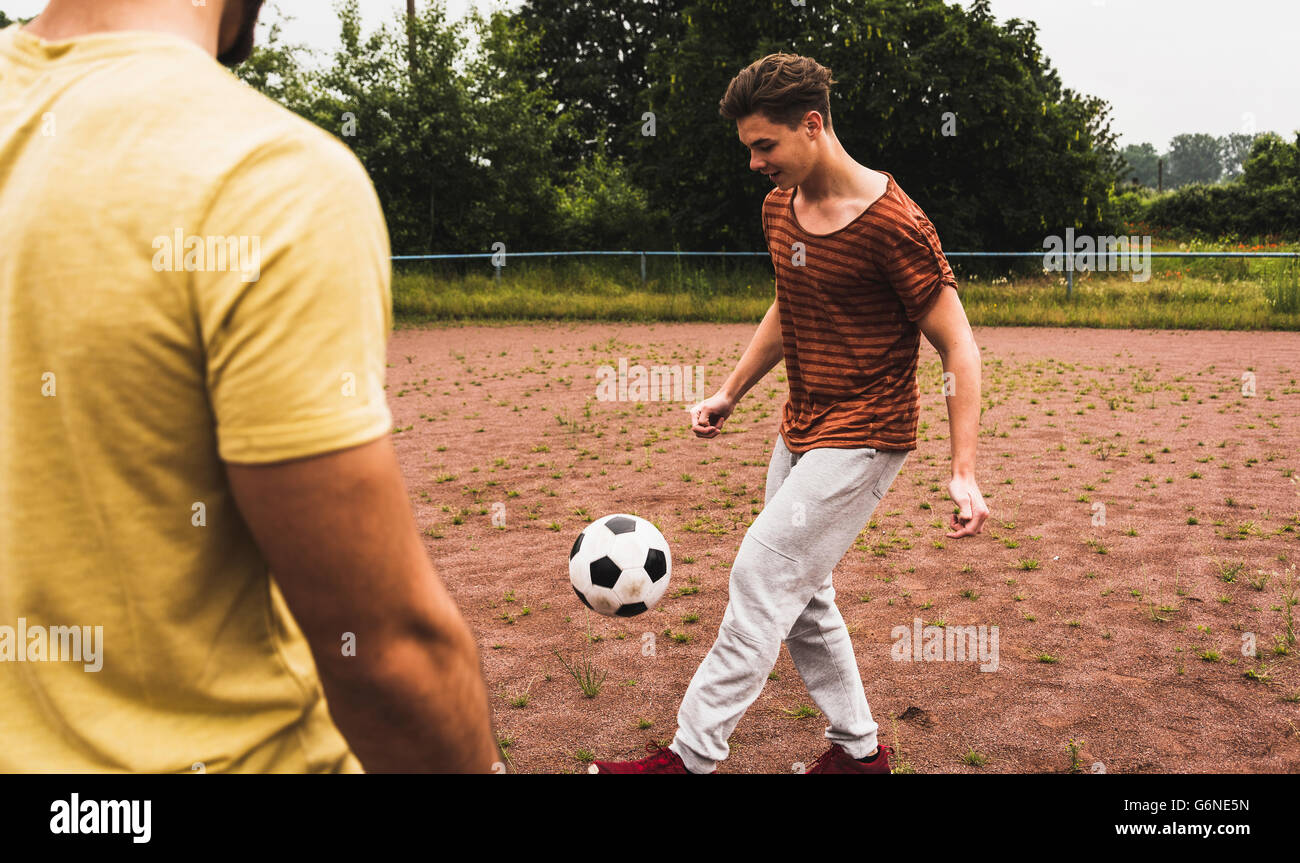 Two men playing football on cinder pitch Stock Photo - Alamy
