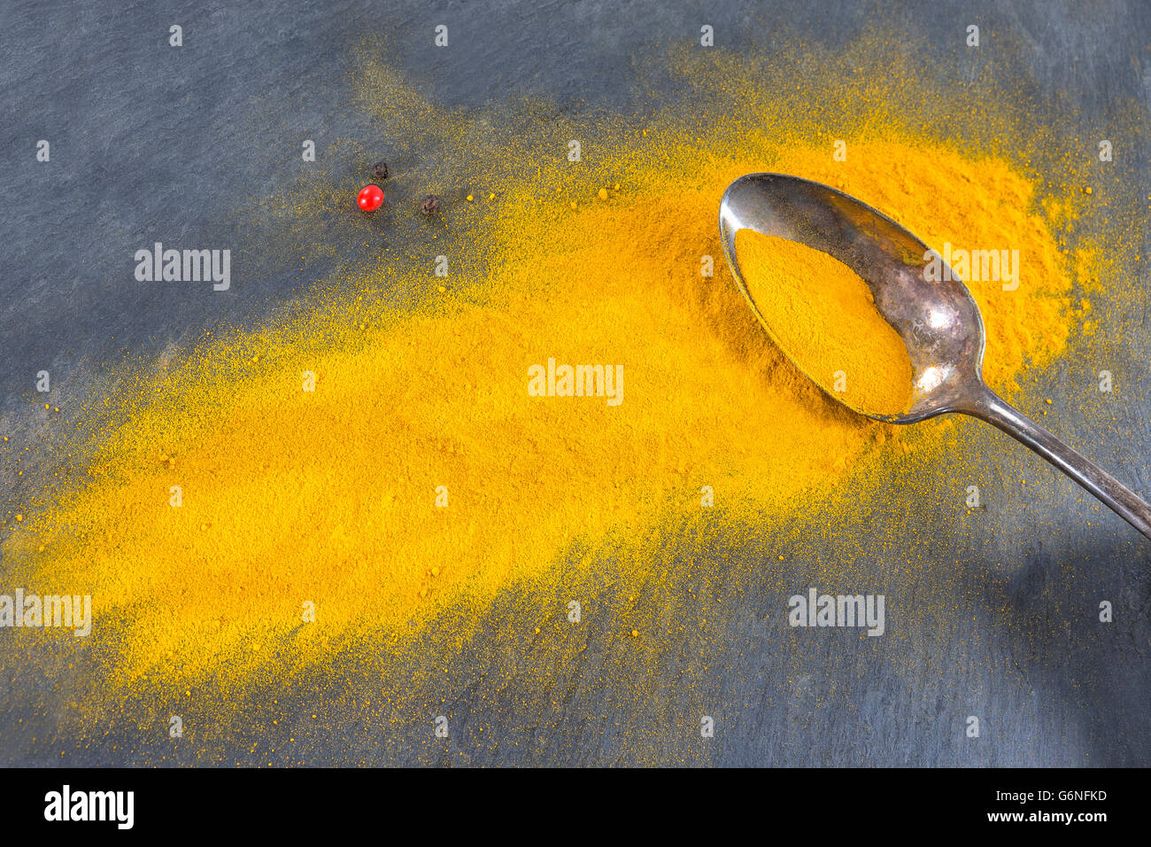 Yellow curry powder in silver spoon, isolated on slate background Stock ...