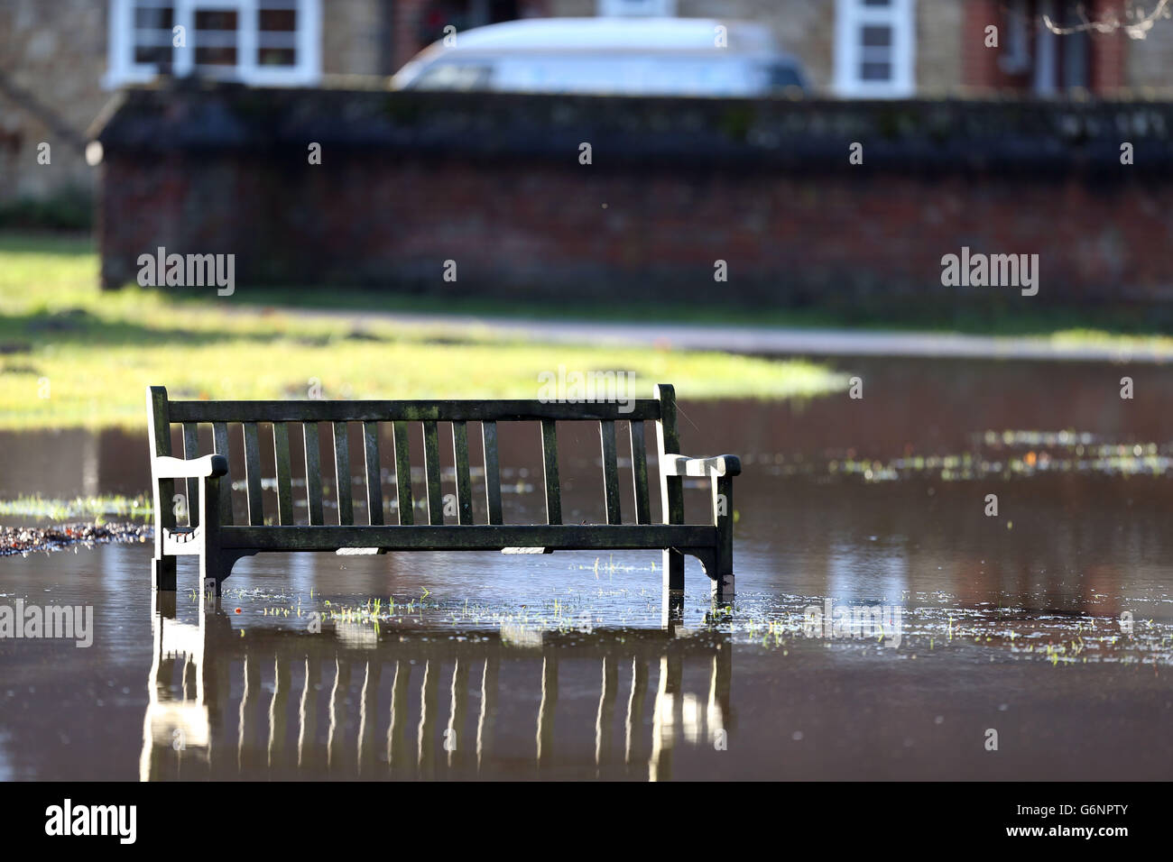 A park bench is surrounded by water in Godalming in Surrey after floods ...