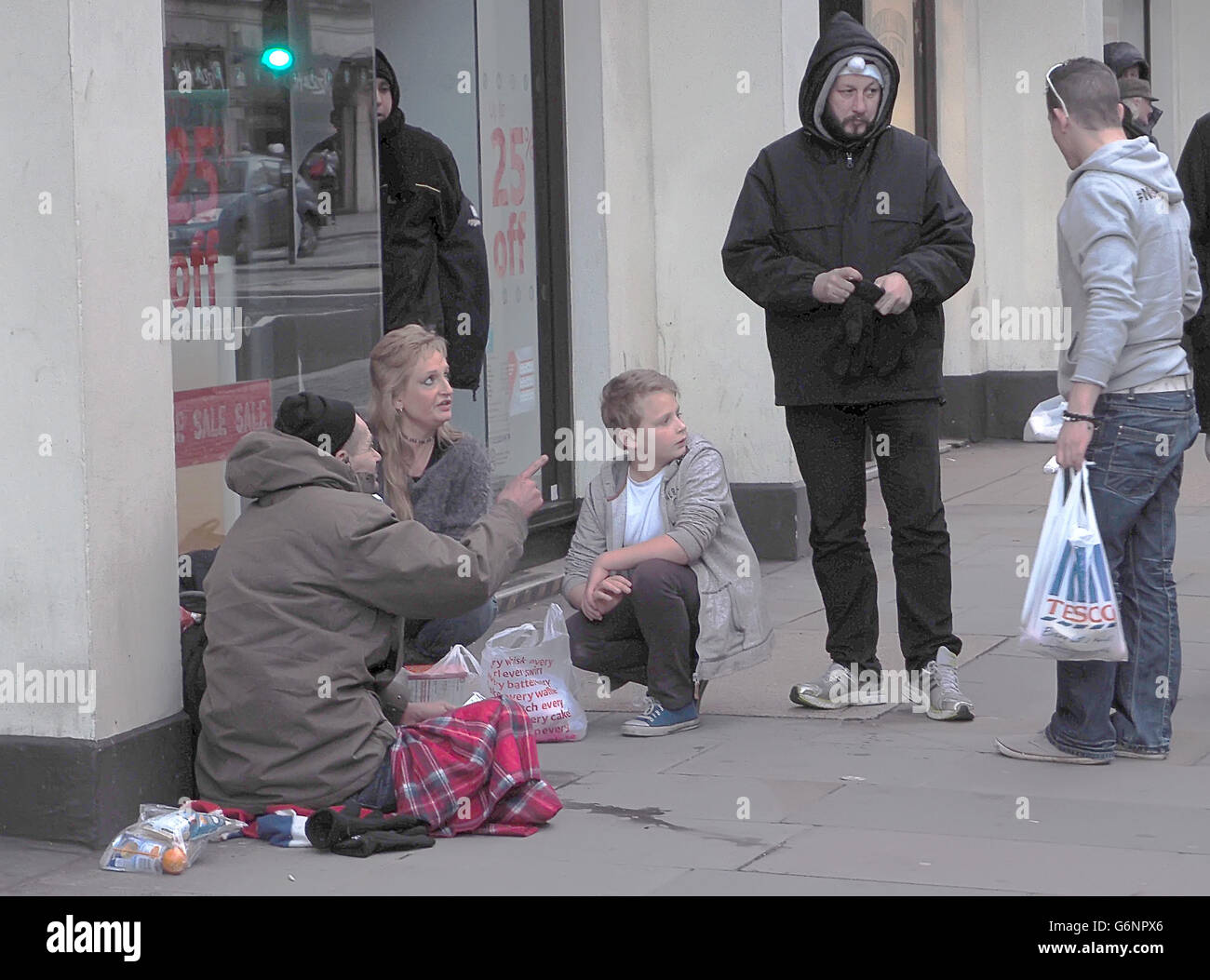 A homeless man (left) receives clothes and food from passers-by on ...