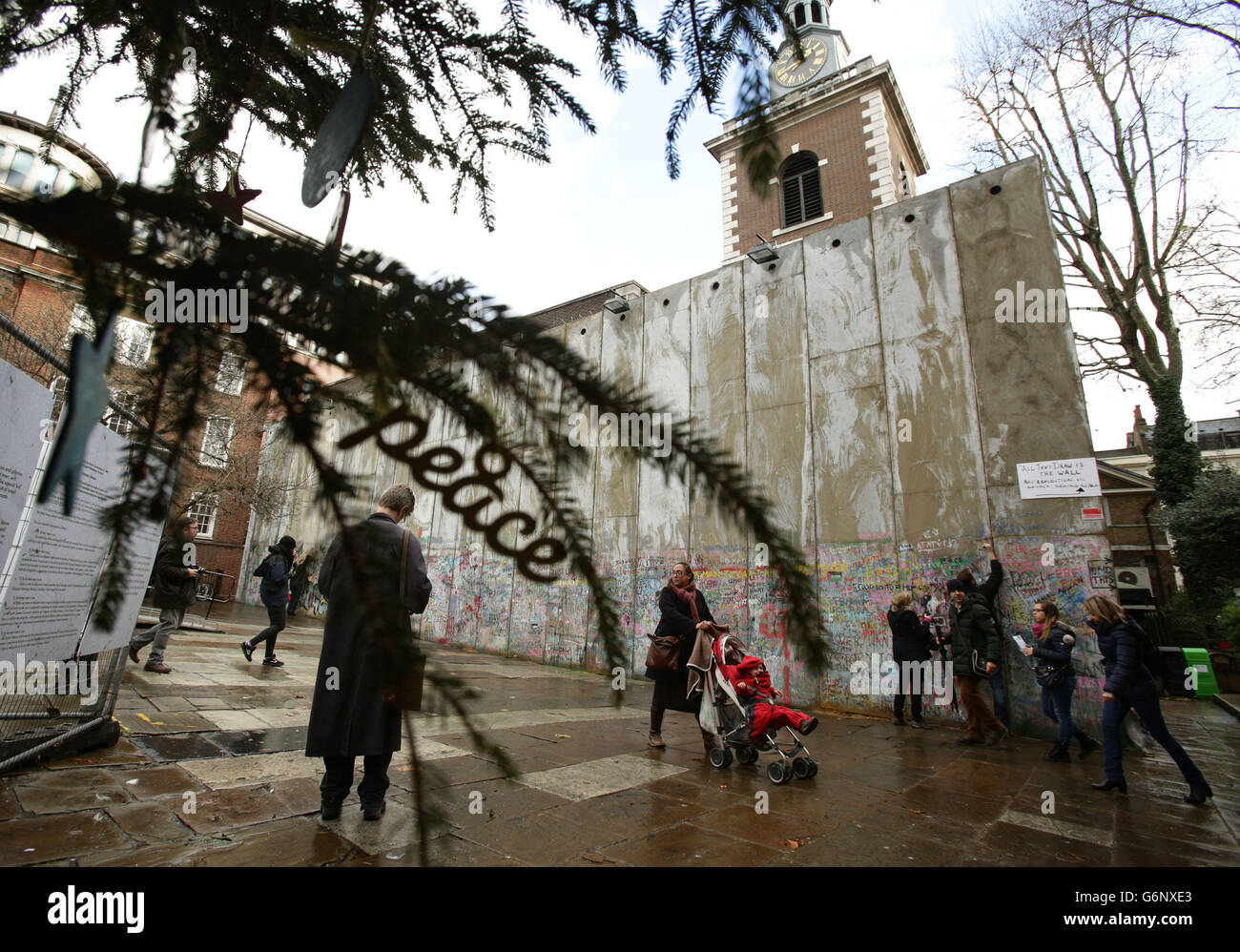 Visitors write messages on and eight metre high wall, a replica of the ...
