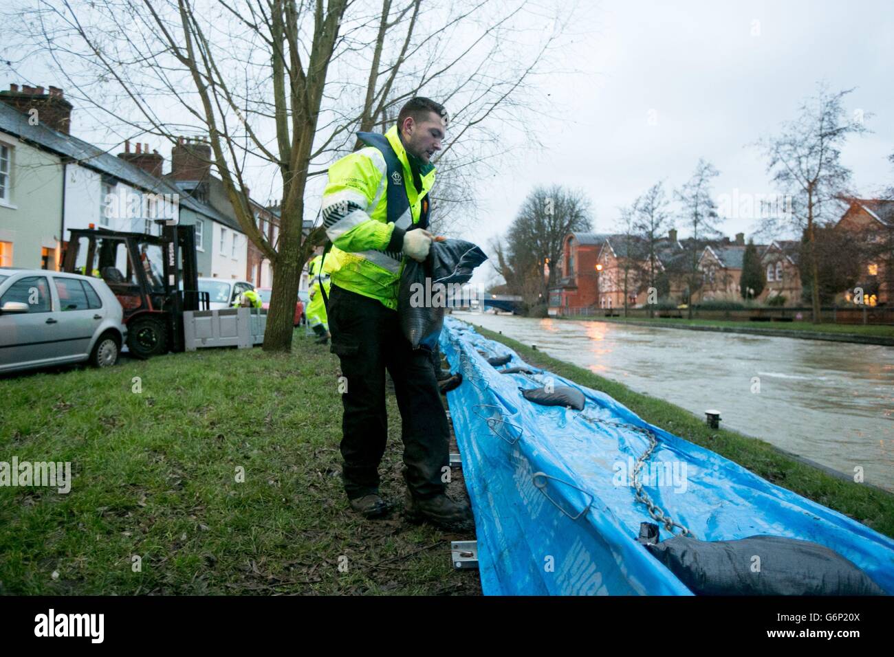 Environment Agency workers lay sandbags onto river defence barriers ...