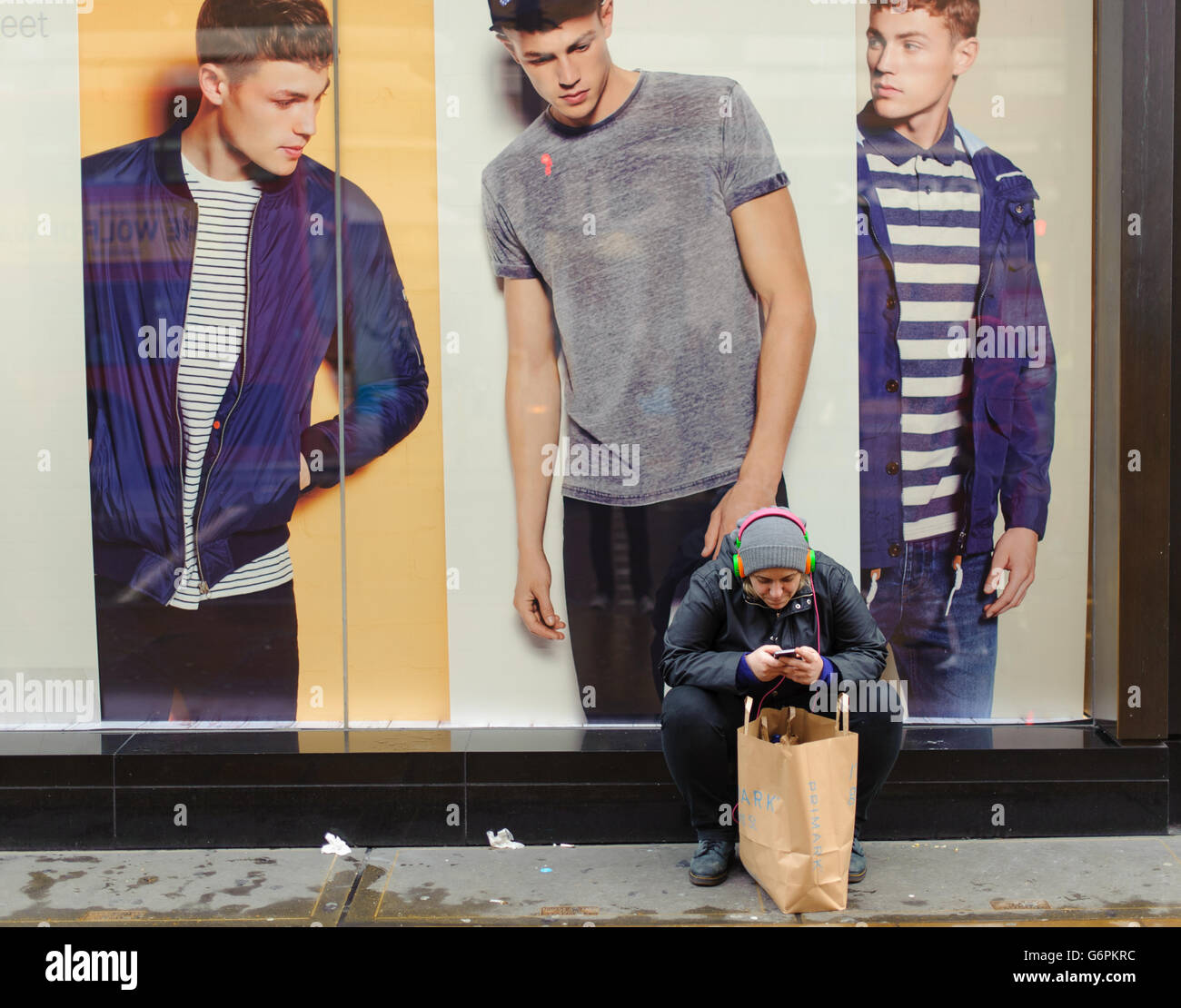 A shopper sits outside a shop window display on Oxford Street, in ...