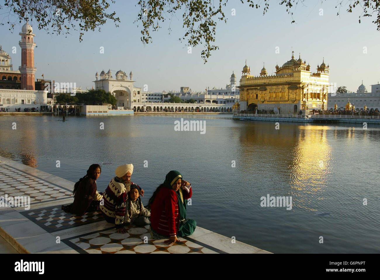 Pilgrims sit at the edge of a moat Stock Photo - Alamy
