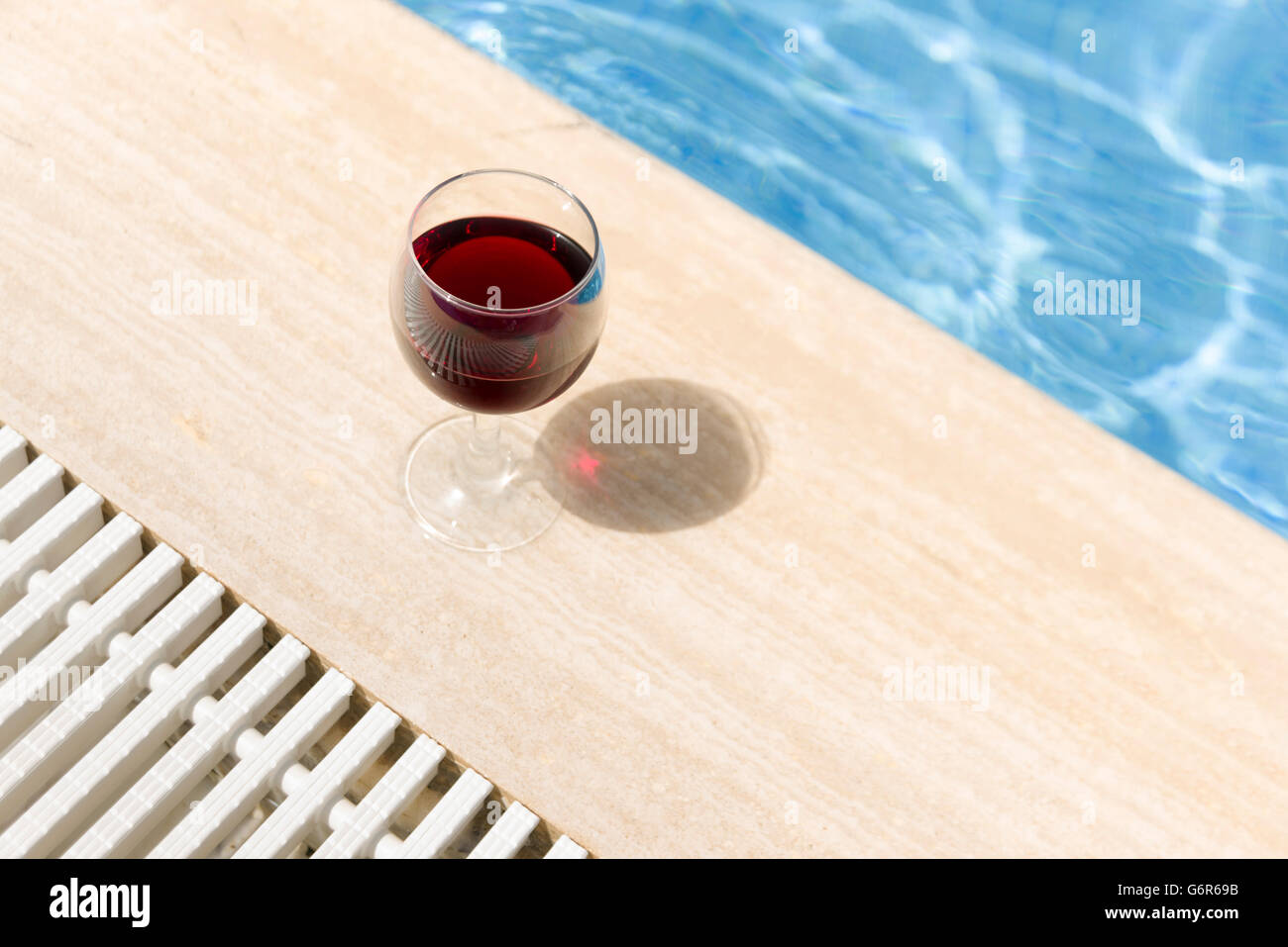 A glass of wine near the swimming pools edge Stock Photo - Alamy