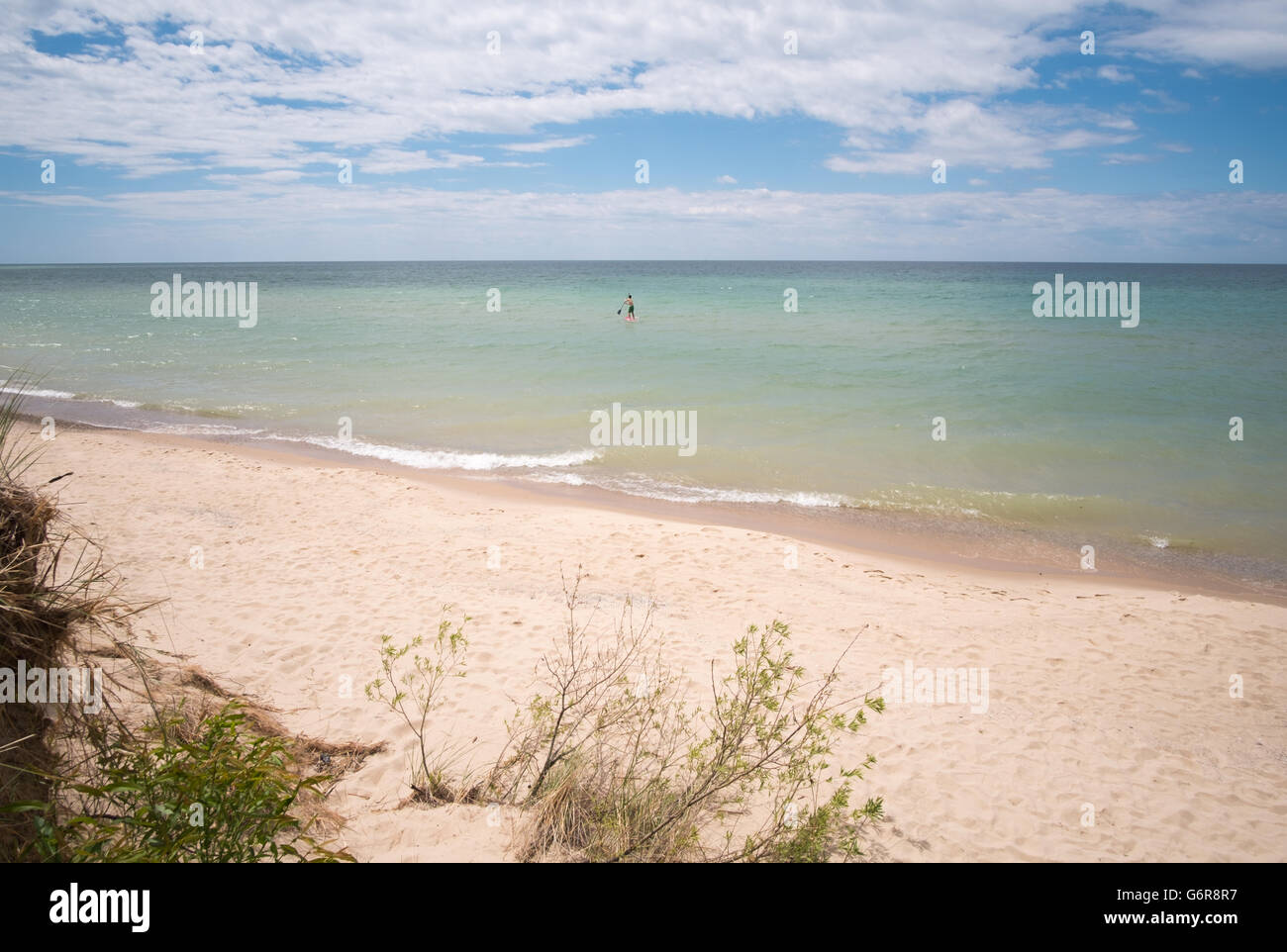 Young man riding a paddle board on Lake Michigan offshore from Arcadia ...
