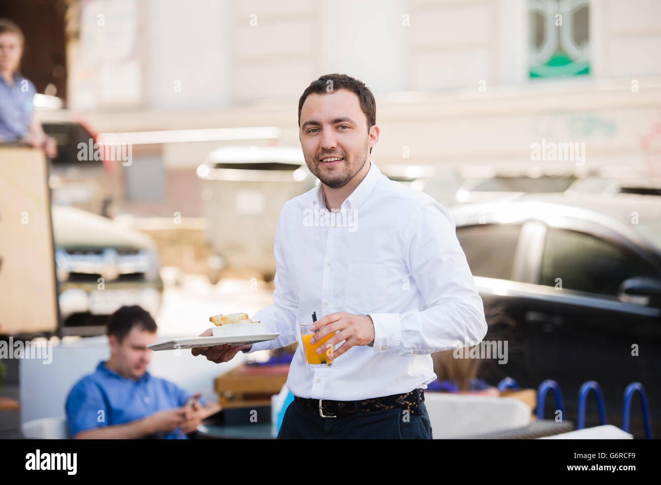 Portrait of happy waiter holding breakfast meal and orange juice at ...