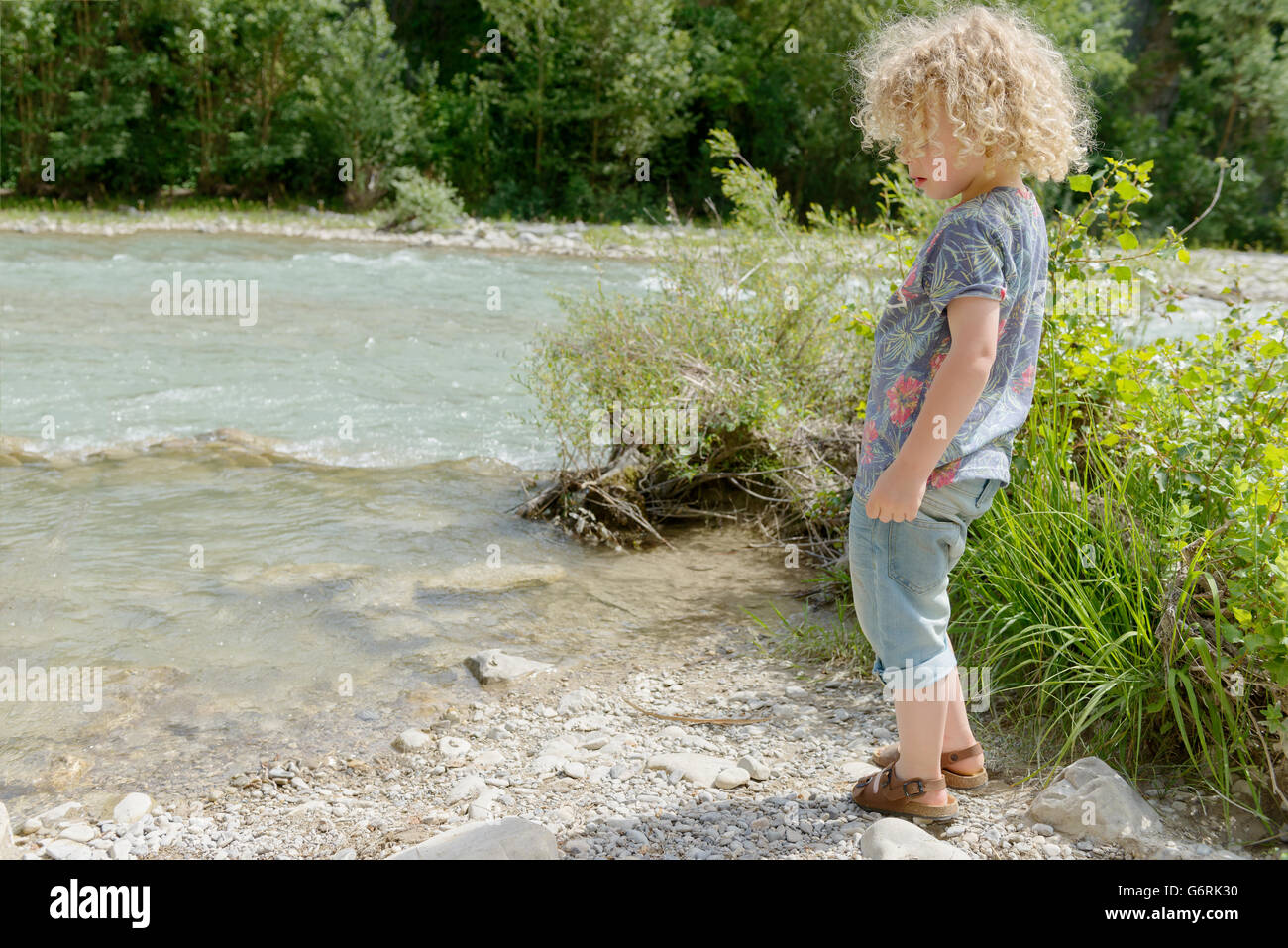 a little boy with curly hair near the river Stock Photo - Alamy