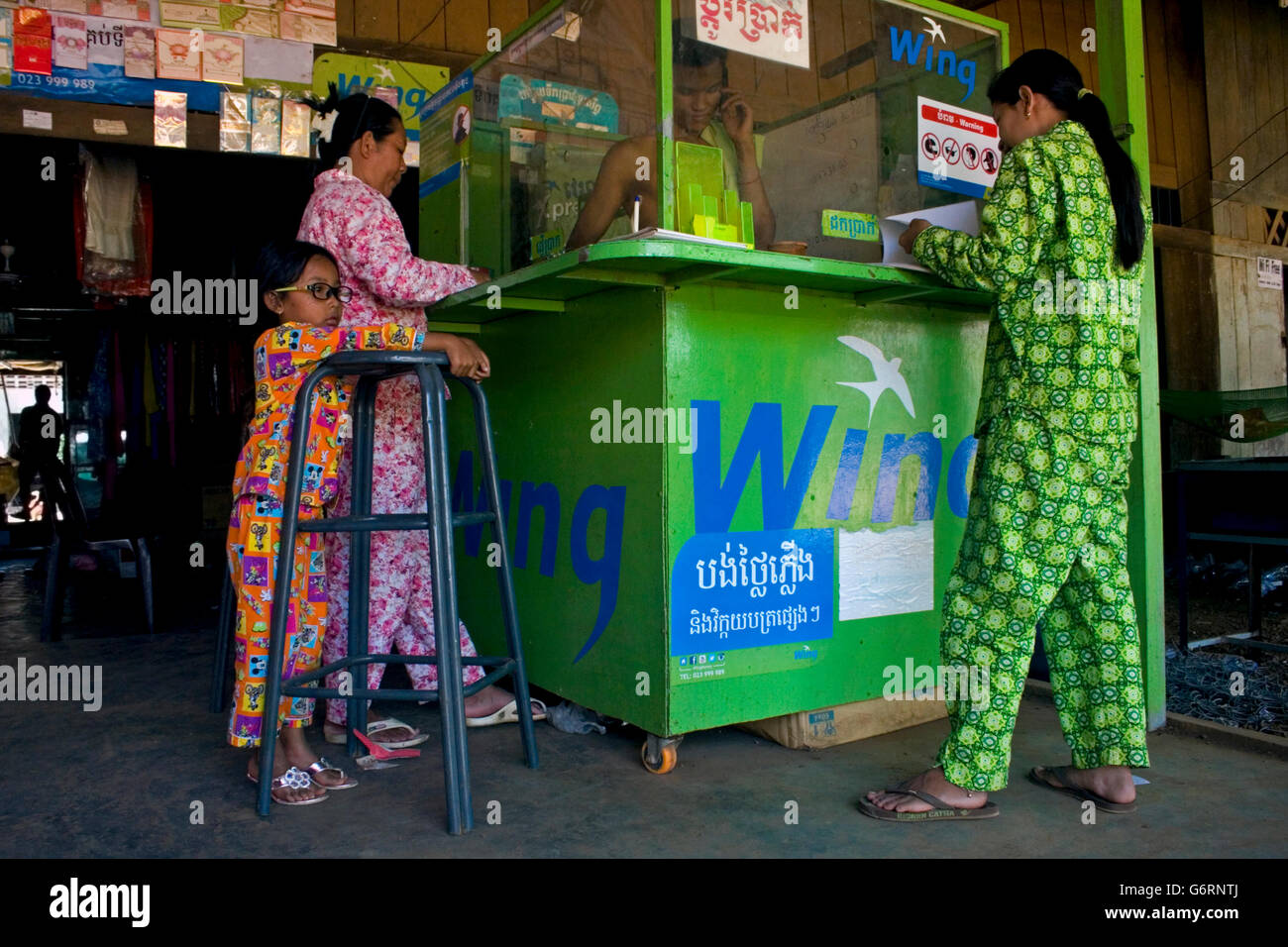 A woman is collecting money at a WING money transfer kiosk in Chork ...