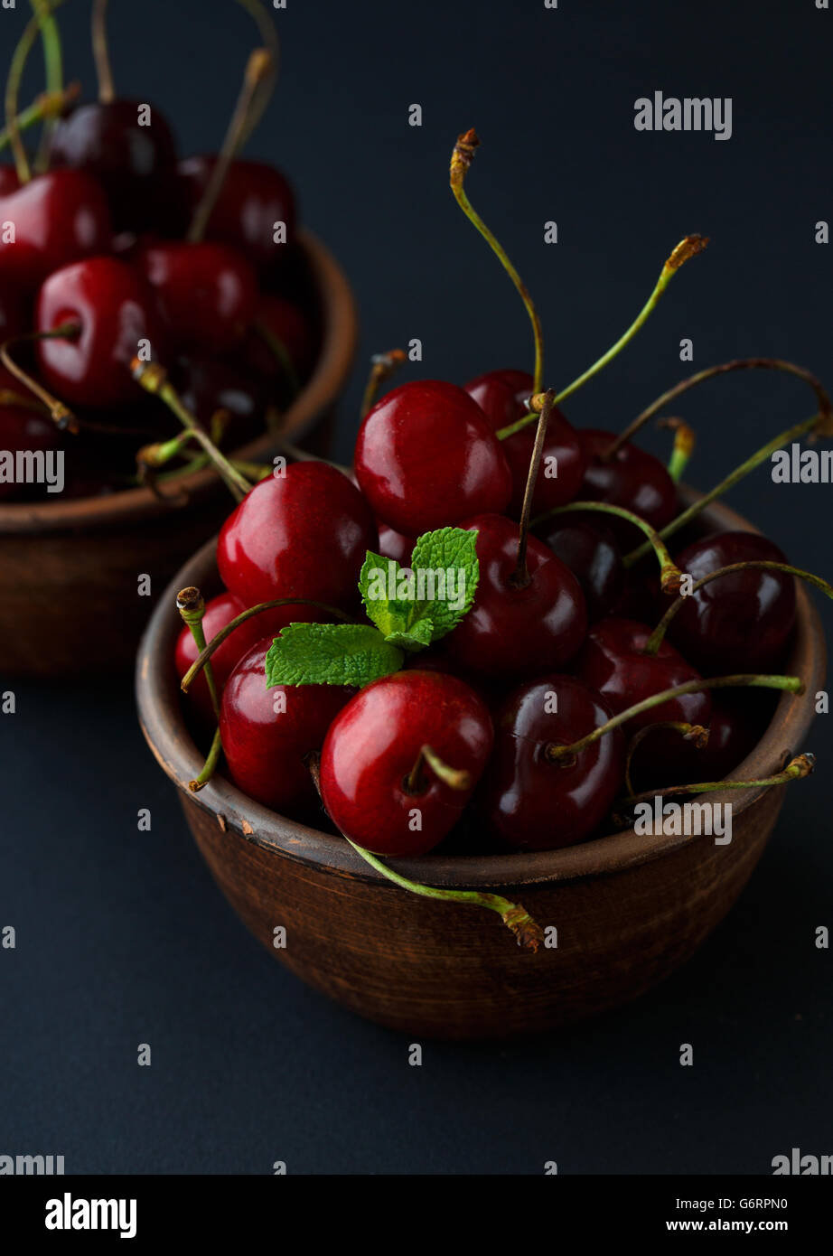 Ripe fresh cherries in a clay bowl on black background Stock Photo - Alamy