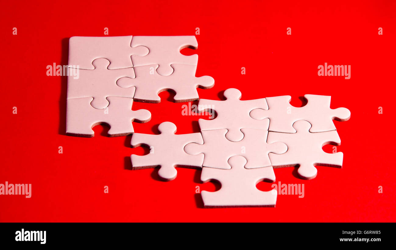 still life with a white jigsaw/puzzle incomplete over a red background ...