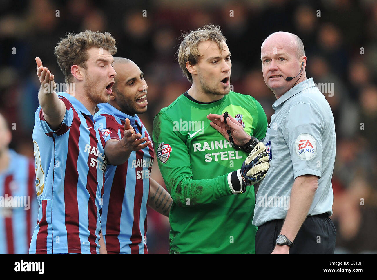 Scunthorpe United players protest to referee Lee Mason after he gives ...