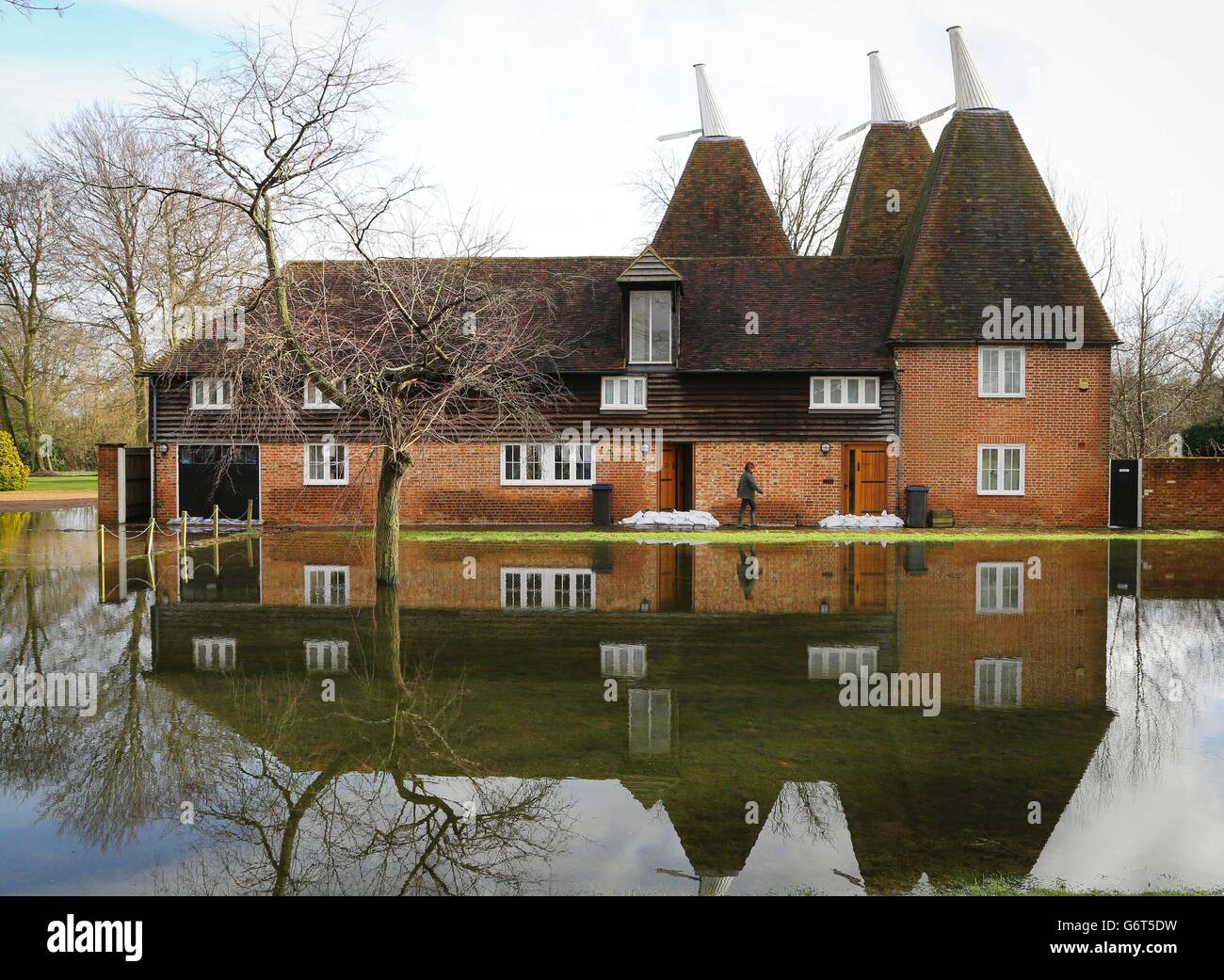 A woman walks past her oast house in Littlebourne, Kent, as river ...