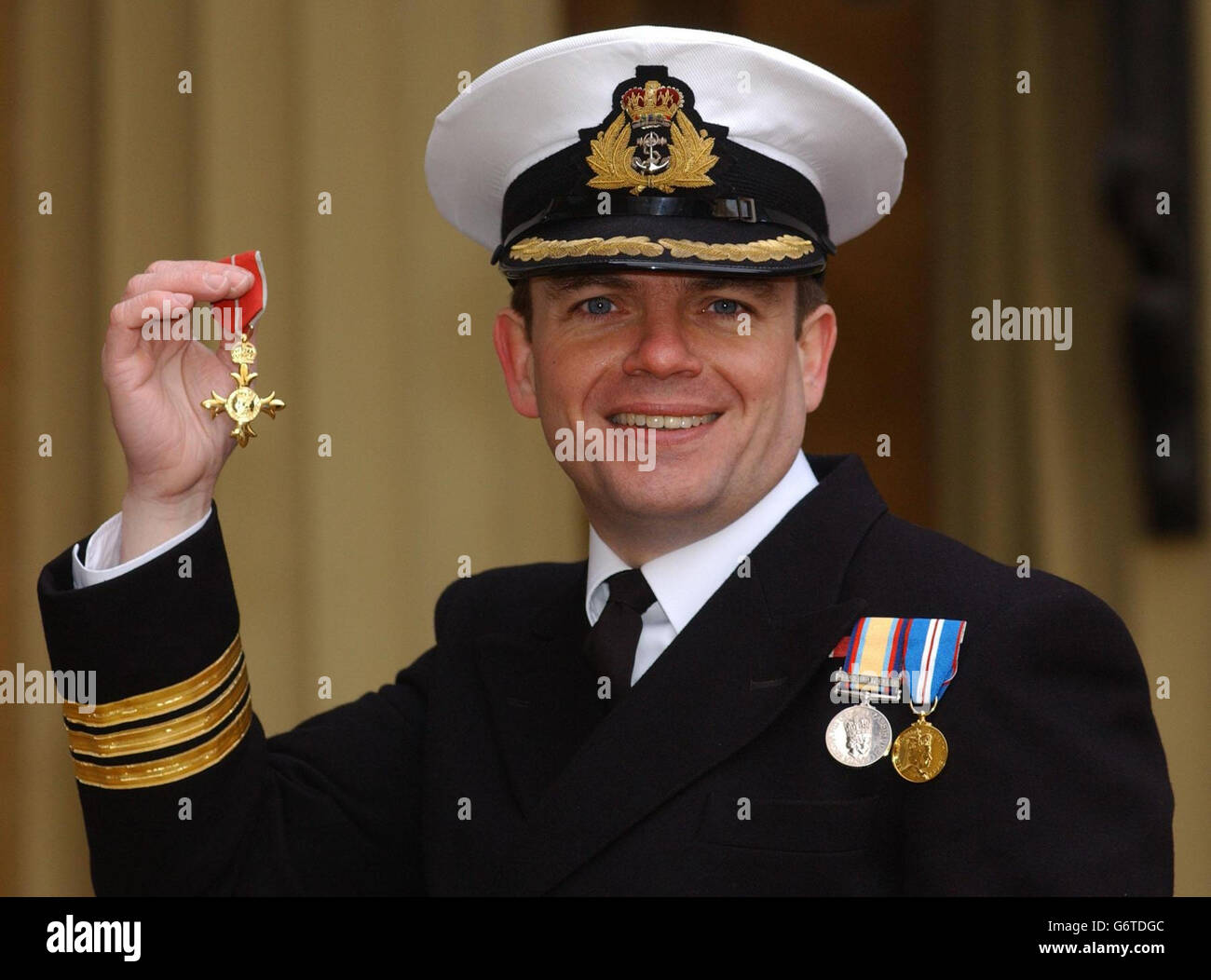 Royal Navy Commander Simon Tate holds his OBE after being decorated by ...