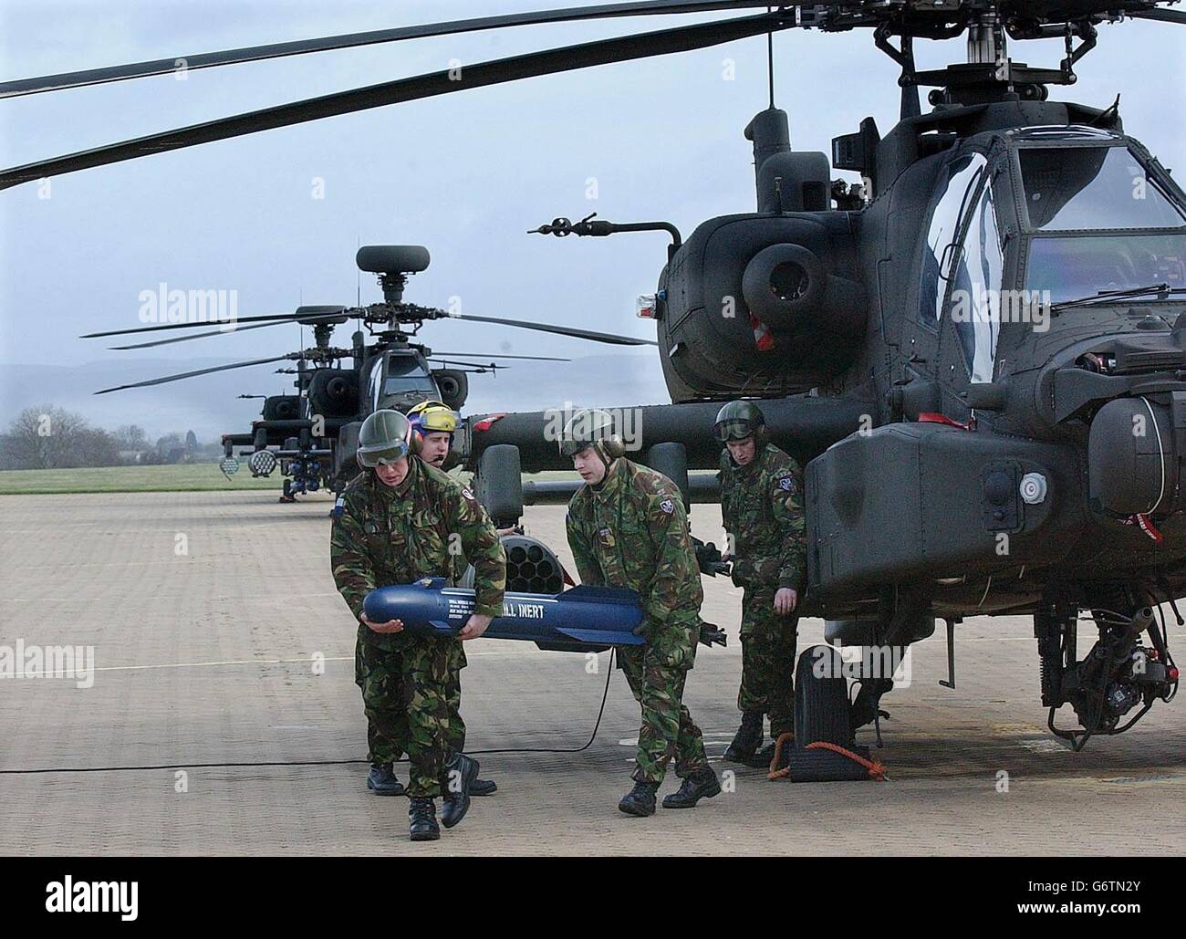 Ground crew carry a Hellfire missile near an Apache AH Mk1 helicopter ...