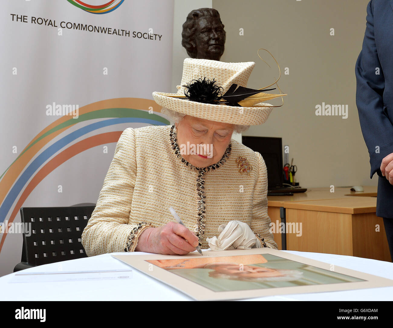 Queen Elizabeth II signs a picture of herself to commemorate a visit ...