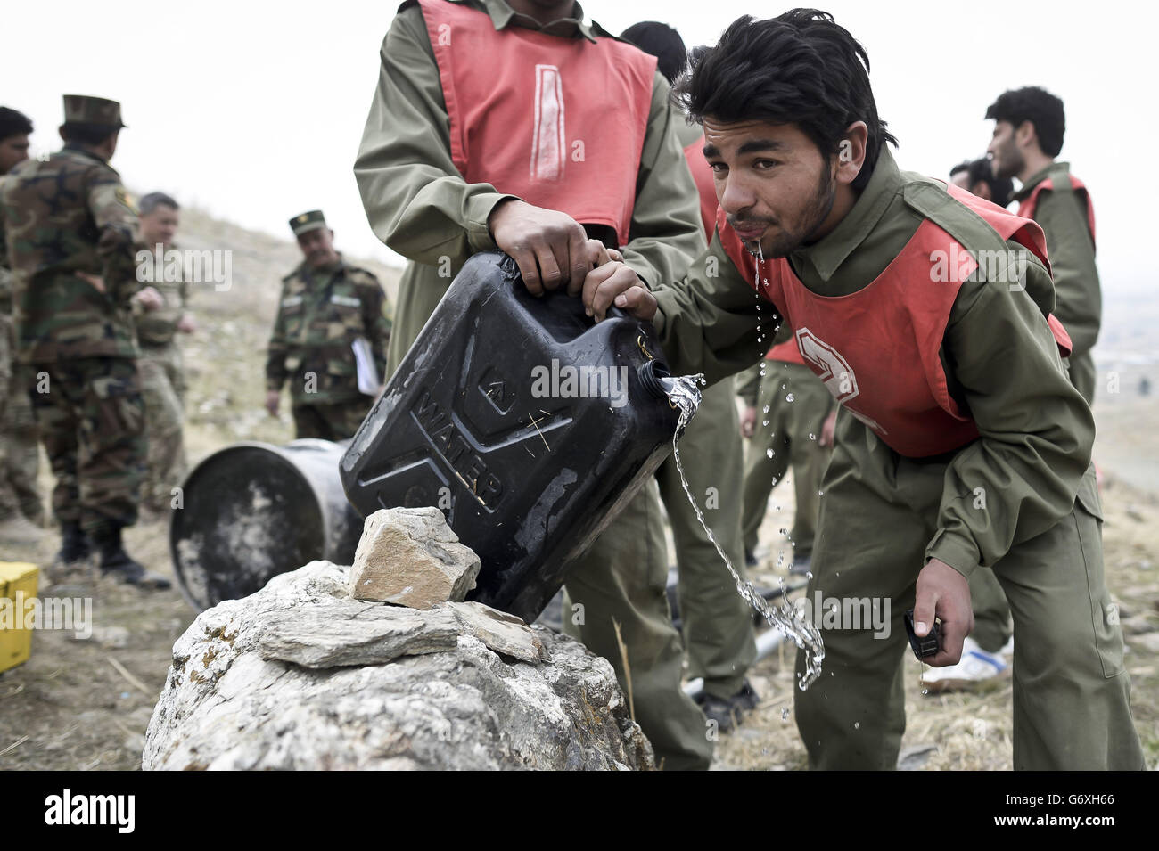An Afghan cadet candidate drinks water from a jerry can on a hillside ...