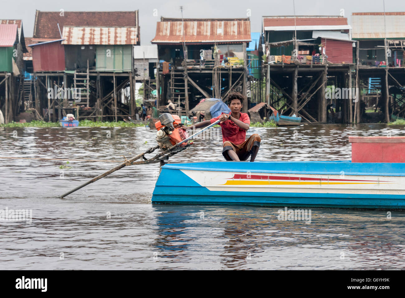 Stilt houses and man driving long tail boat, Kampong Phluk, Tahas River ...