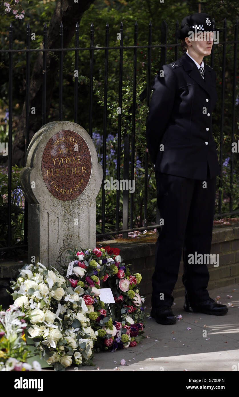 A police officer stands beside floral tributes during a memorial ...