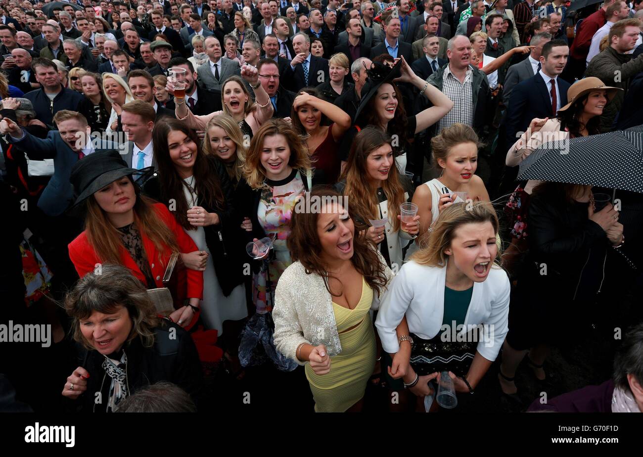 The crowd cheer on the runners in the first race during Grand National ...
