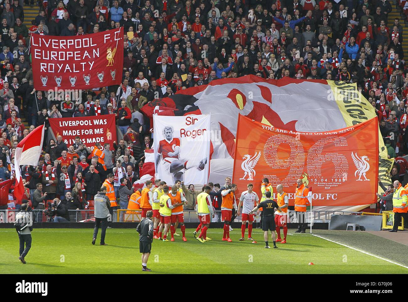 Liverpool players during warm up in front of fans displaying banners in ...