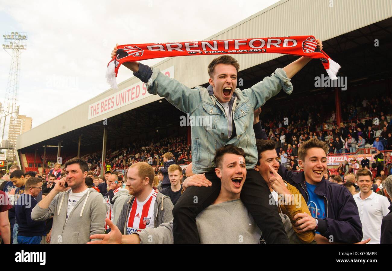 Brentford fans celebrate on the pitch after winning promotion during ...