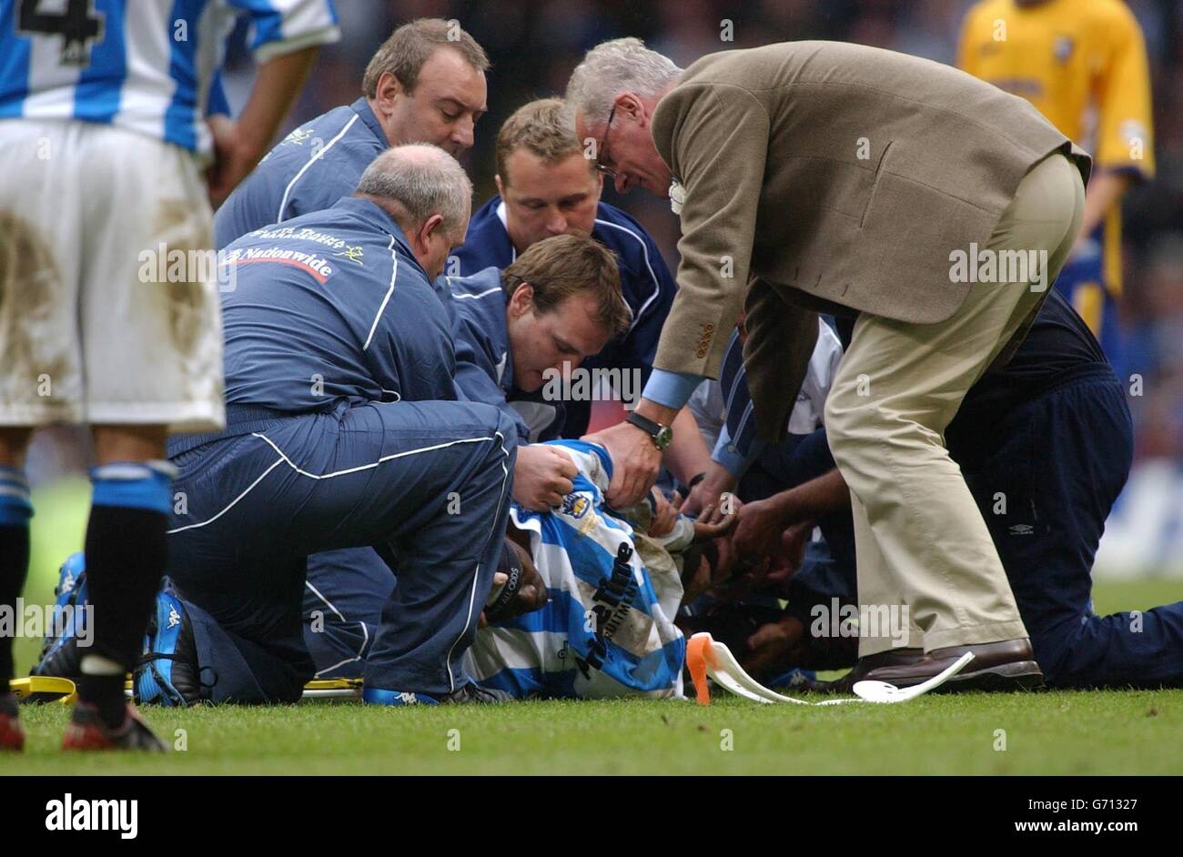 Concerned team officials from Huddersfield gather round Efetobore Fodje ...