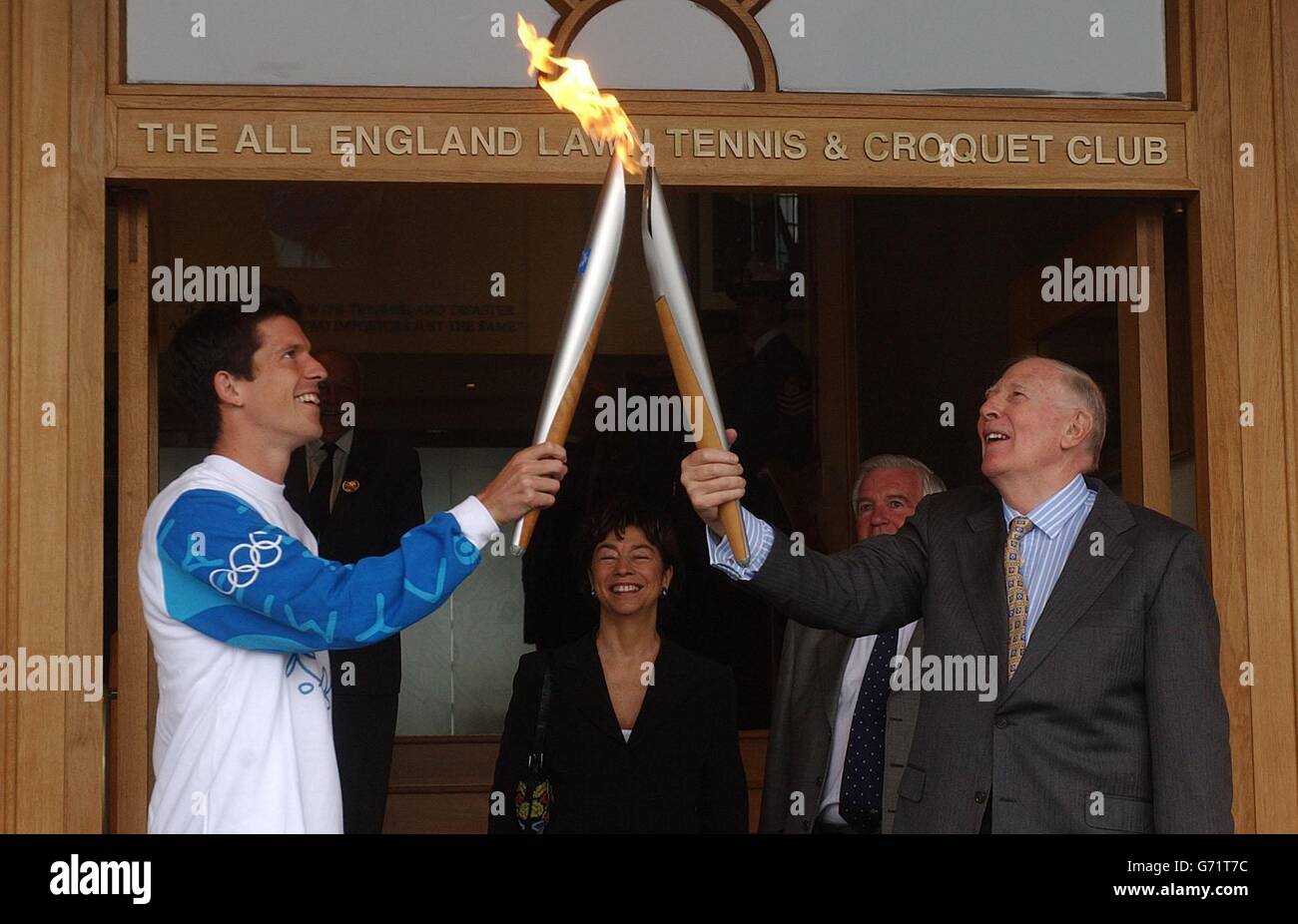 Tim Henman receives the Olympic torch from Sir Roger Bannister outside ...